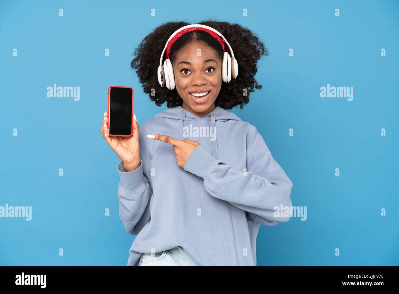 Young black woman in headphones pointing finger at her cellphone ...