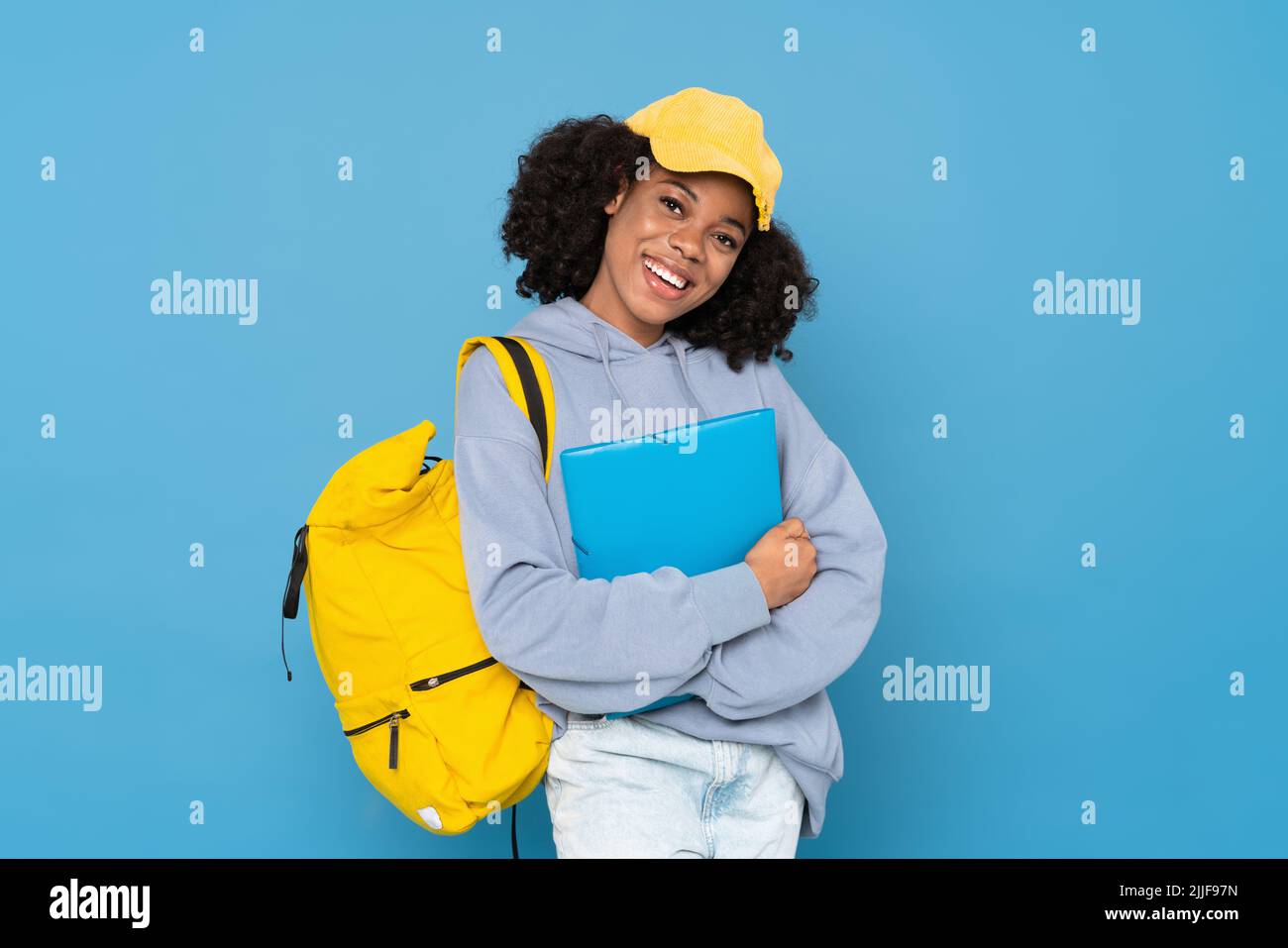 Young black woman smiling while posing with backpack and folder ...