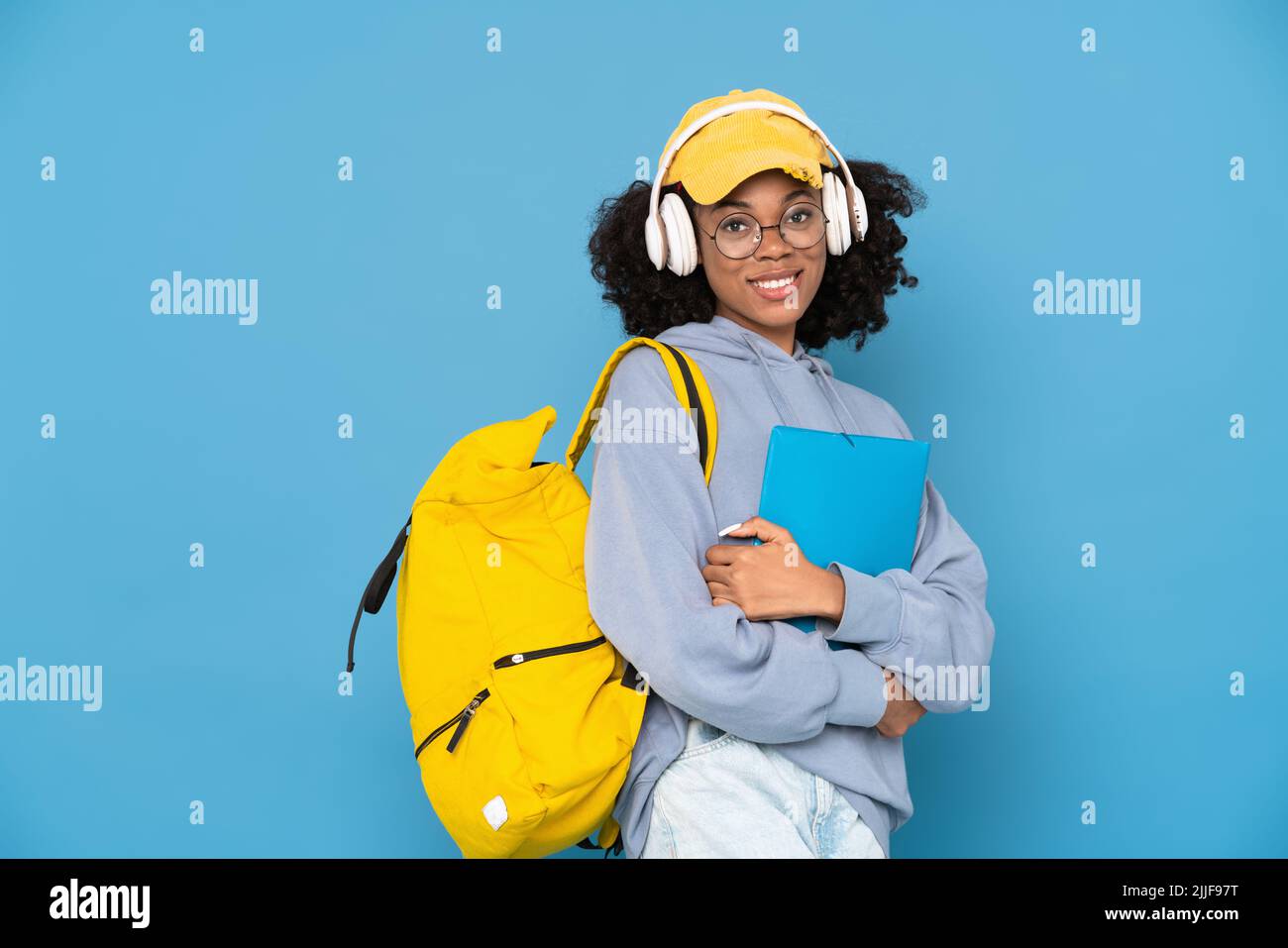 Young black woman smiling while posing with backpack and folder ...