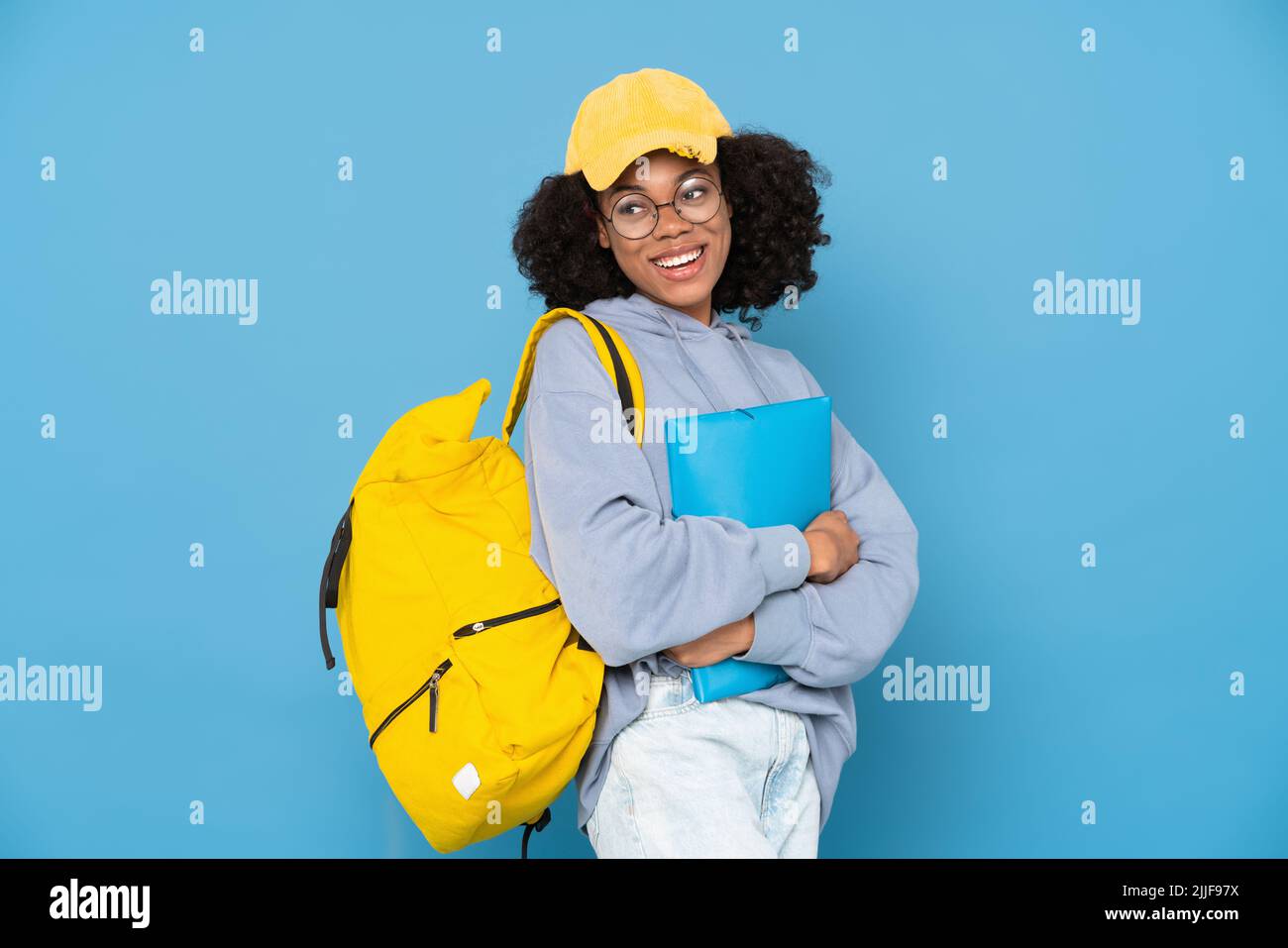 Young black woman smiling while posing with backpack and folder ...