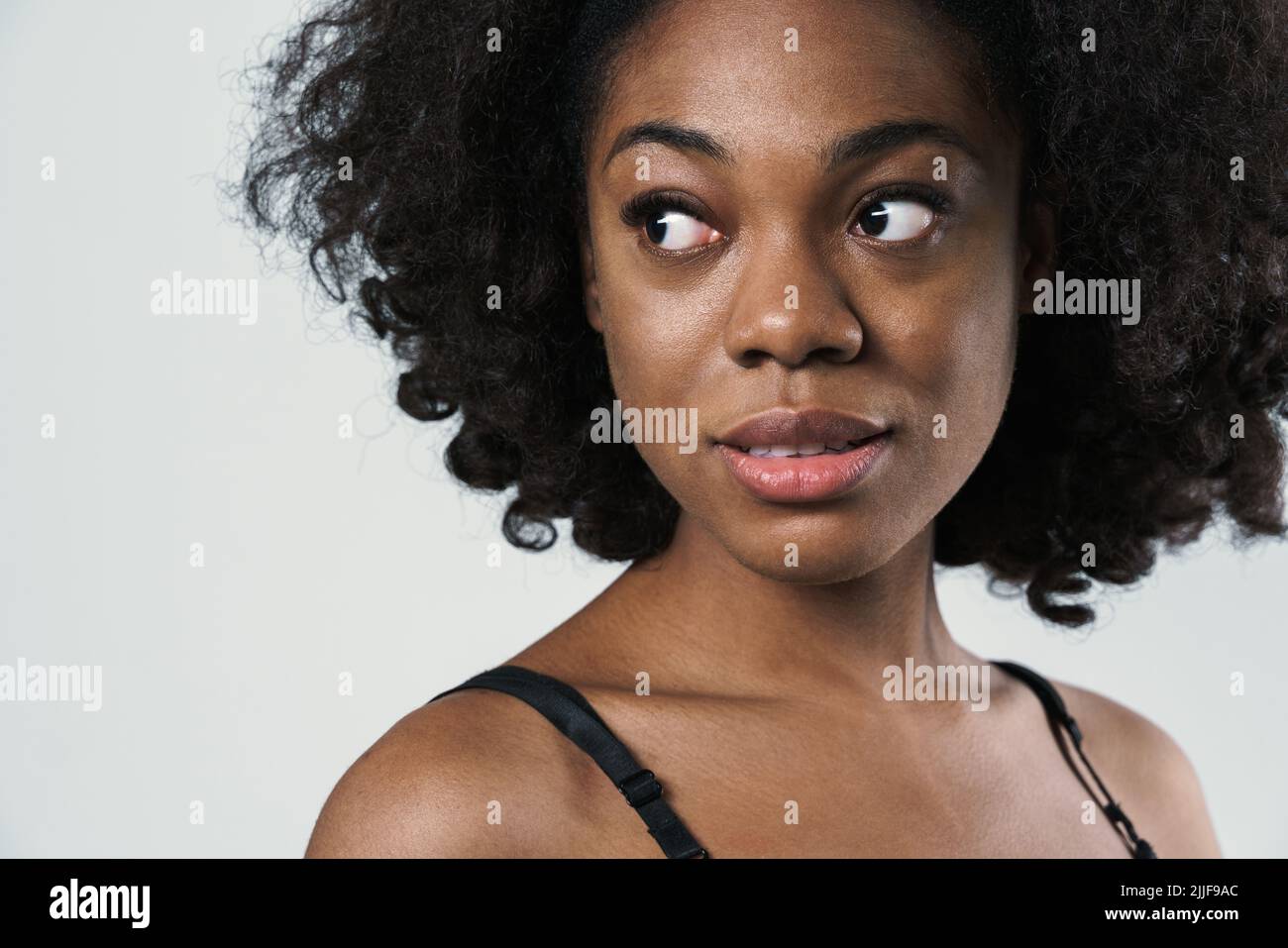 Young black woman in bra posing and looking aside isolated over white ...