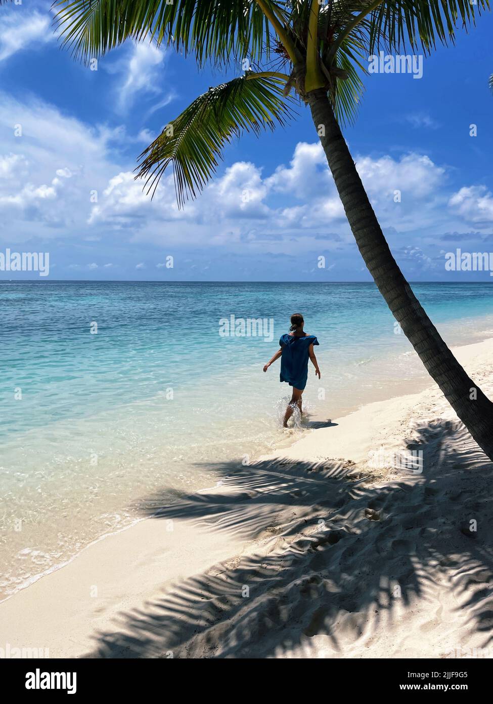 Back view of young woman walking on a tropical beach Stock Photo - Alamy