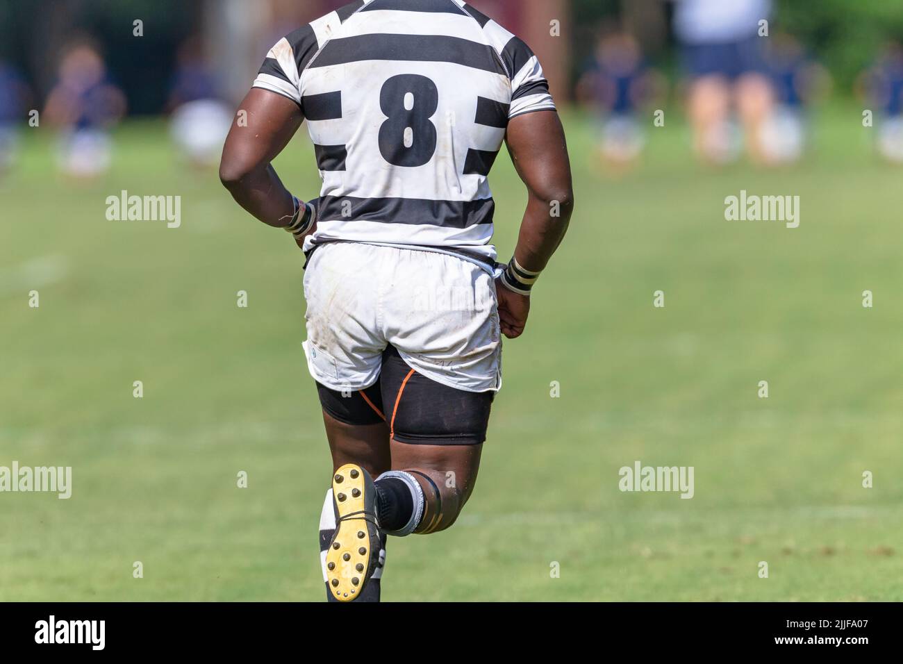 Rugby player headless running on game field close-up rear behind ...