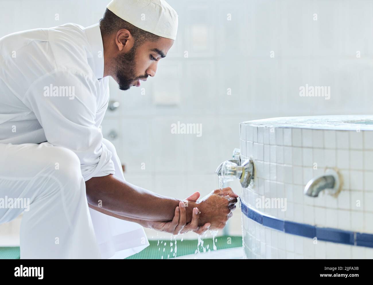 Preparations for prayer time. a young man washing his hand in a mosque ...