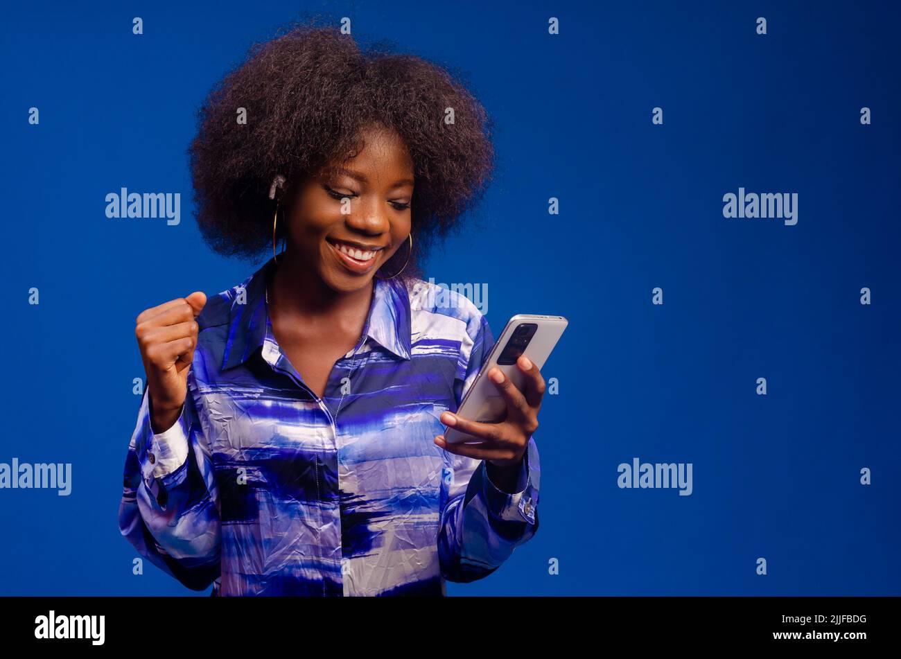 A Beautiful Afro American Lady Feeling Excited About What She Saw On Her Phone In A Blue