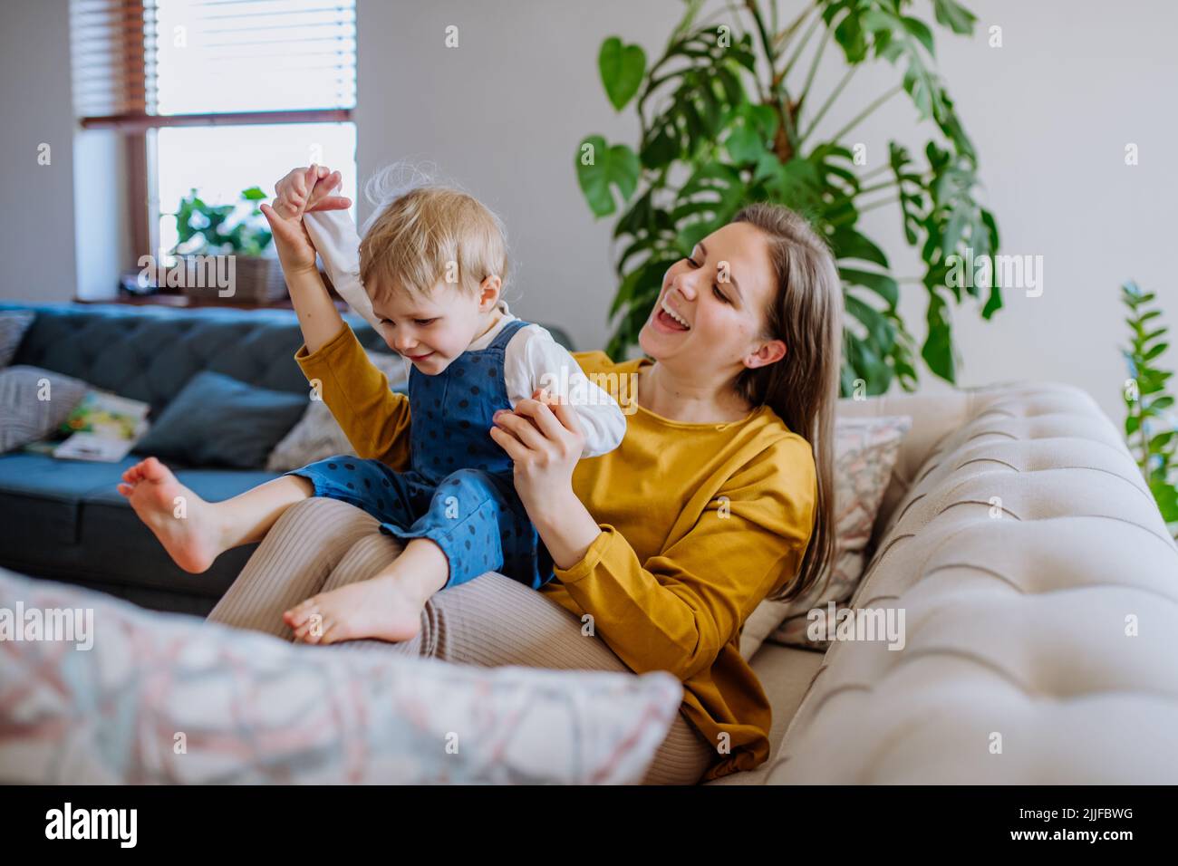 Young cheerful mother playing with her little child and having fun when ...