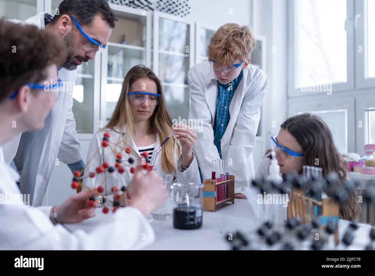 Science students with teacher doing chemical reaction experiment in the ...
