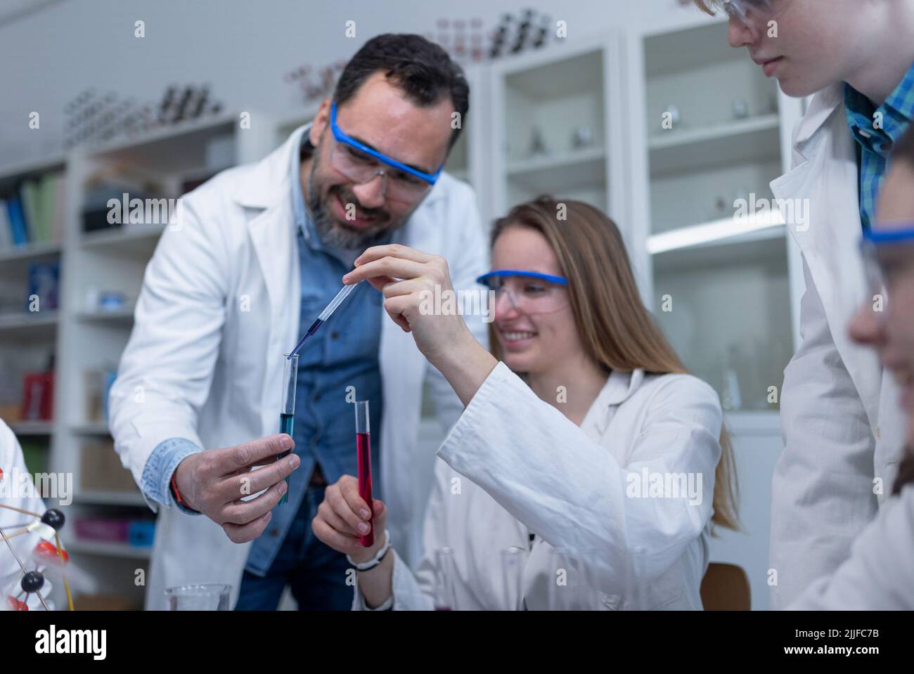 Science students with teacher doing chemical experiment in the ...