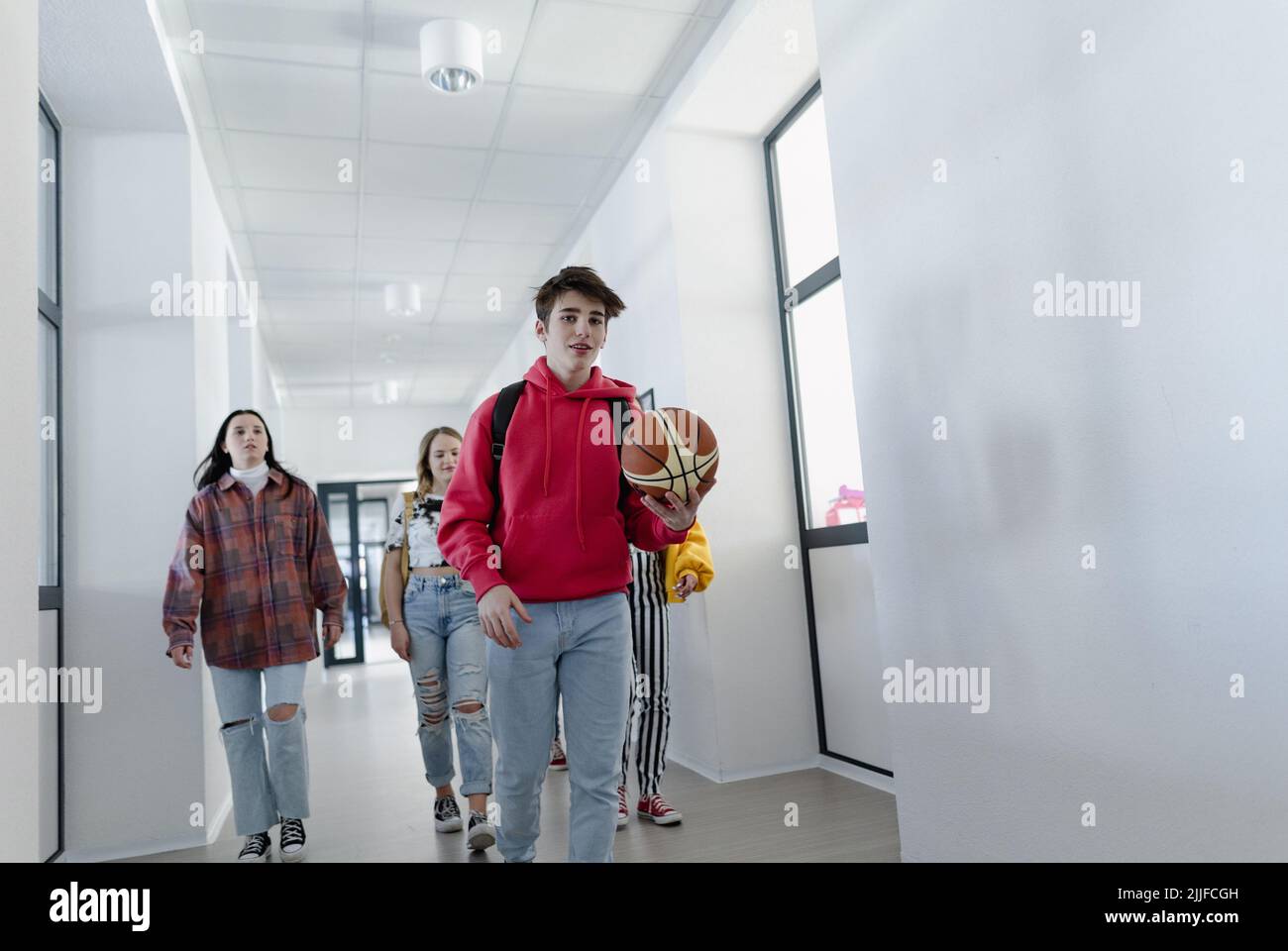 Young high school students walking in corridor at school, back to ...