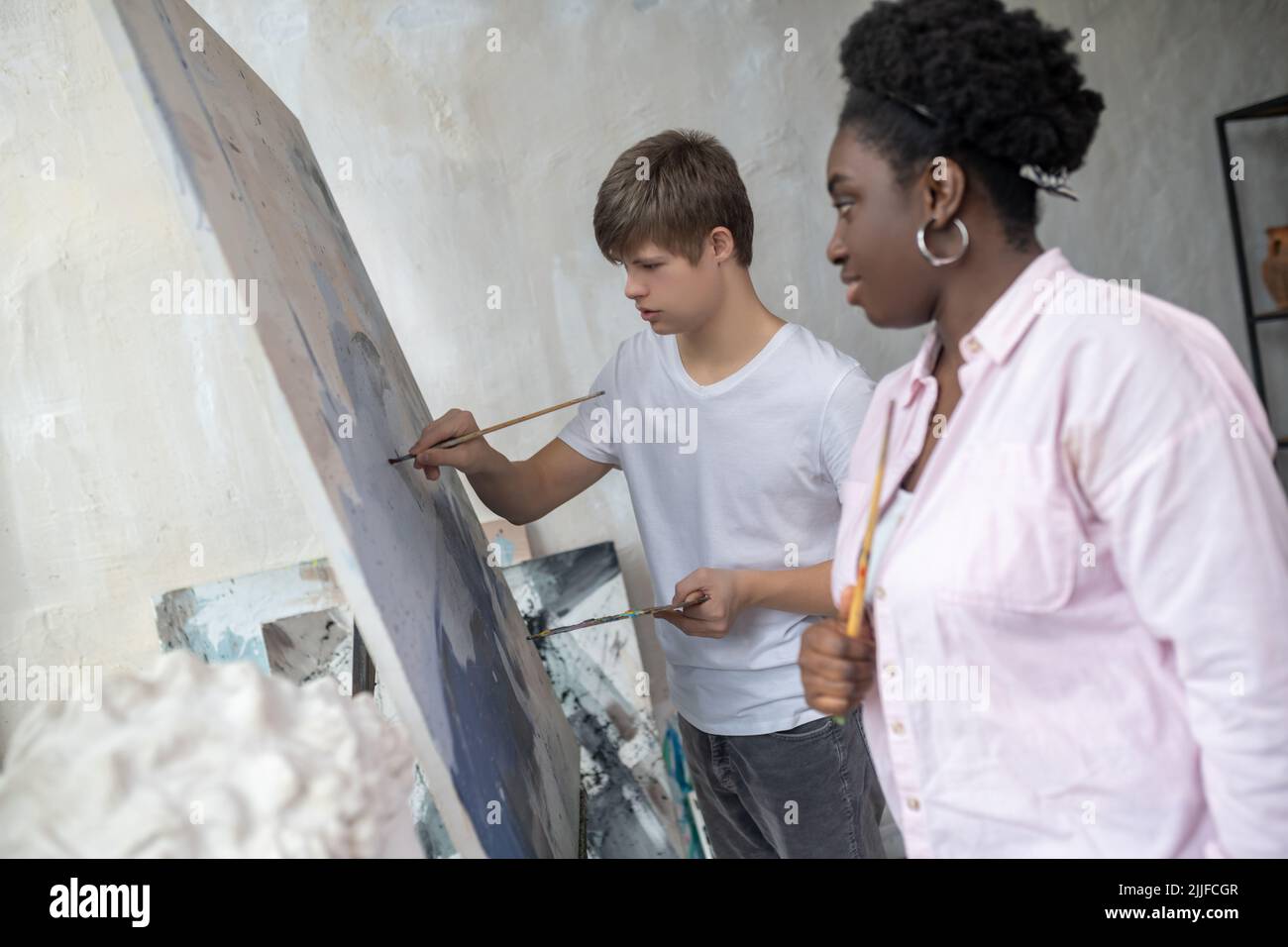A boy standing near the easel and drawing with great involvement Stock ...