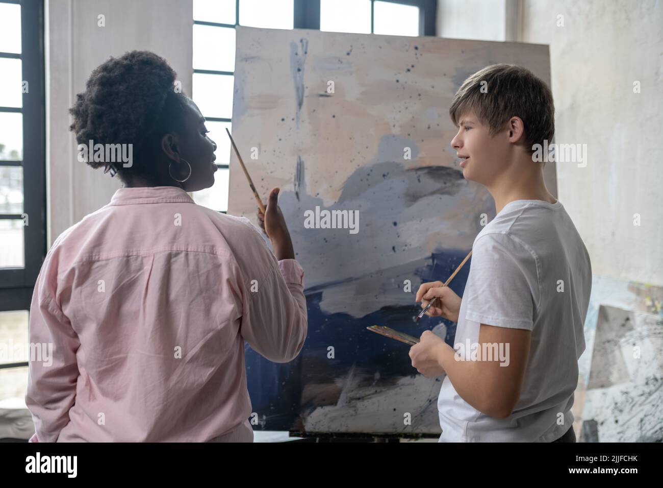 A boy standing near the easel and drawing with great involvement Stock ...