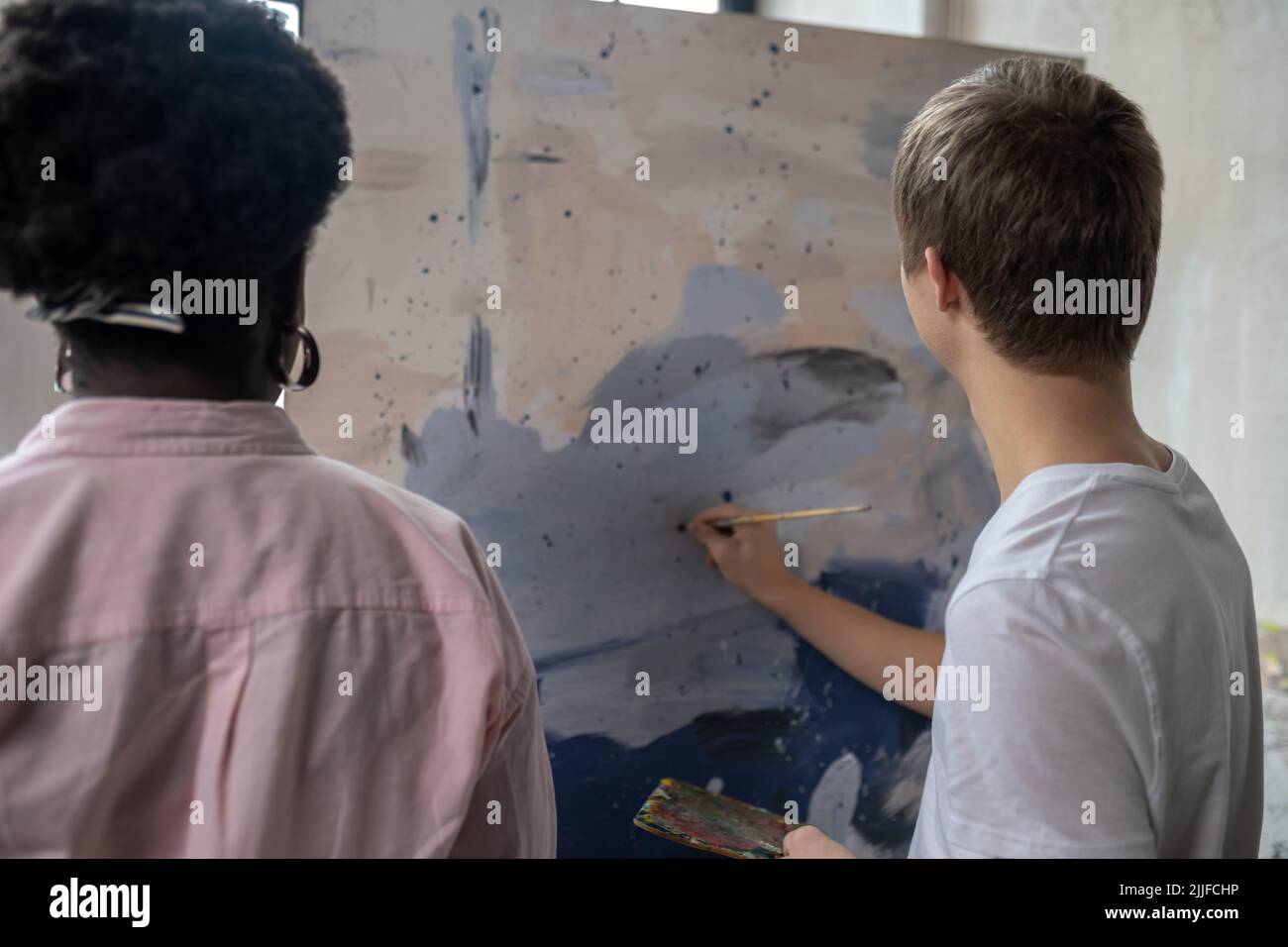 A boy standing near the easel and drawing with great involvement Stock ...