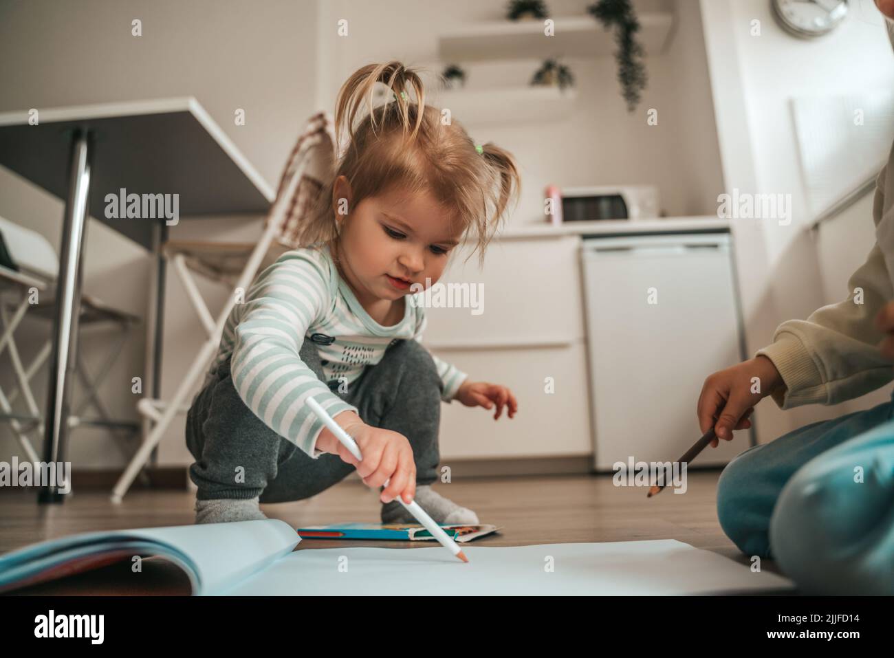 Two children playing on the kitchen floor Stock Photo - Alamy