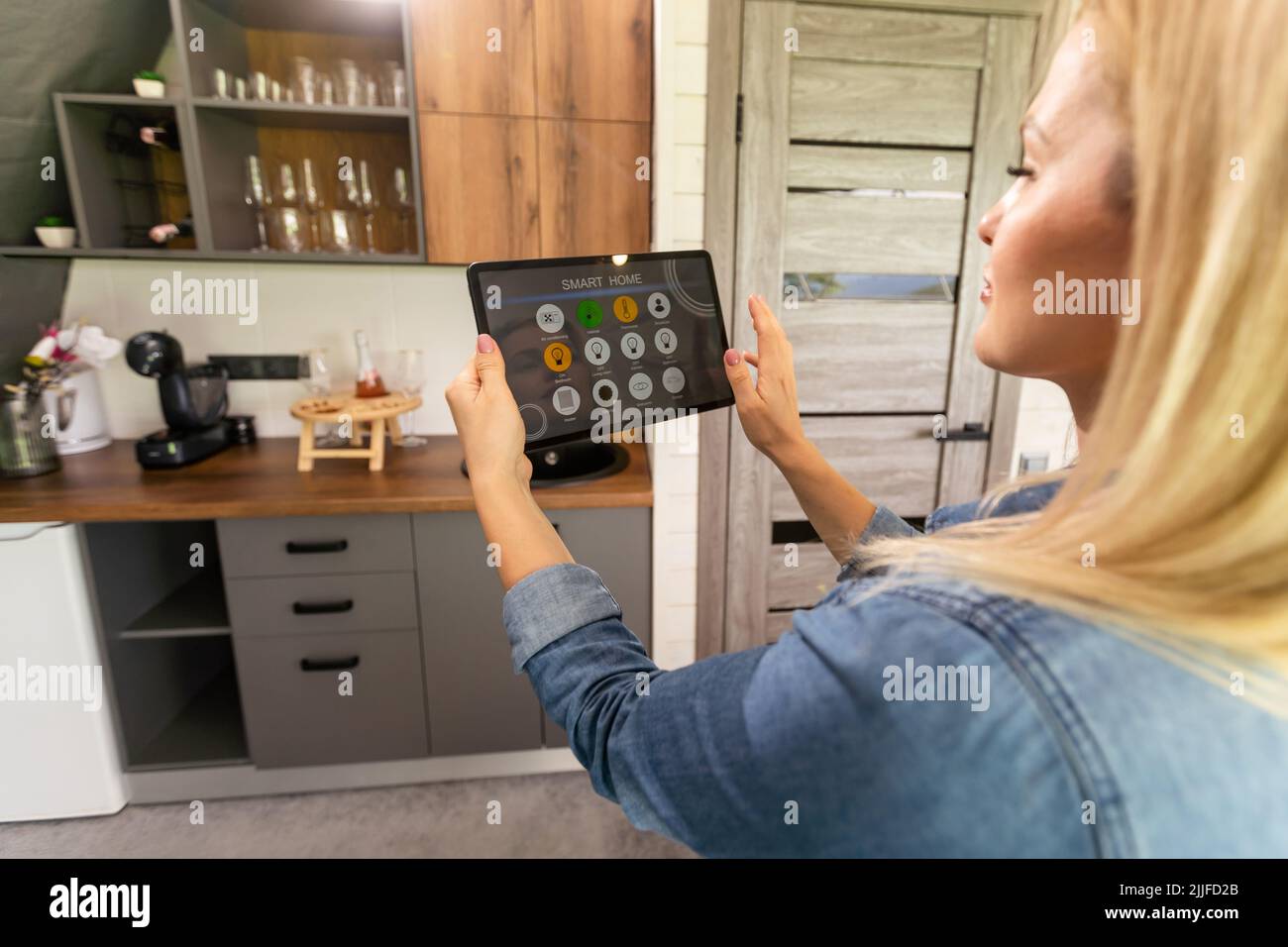 hands holding smart tablet with app smart home on .home living room as ...