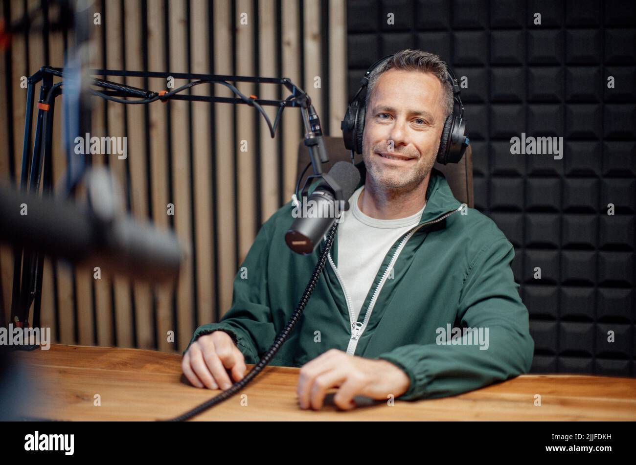Portrait of mature radio host speaking in microphone while moderating a ...