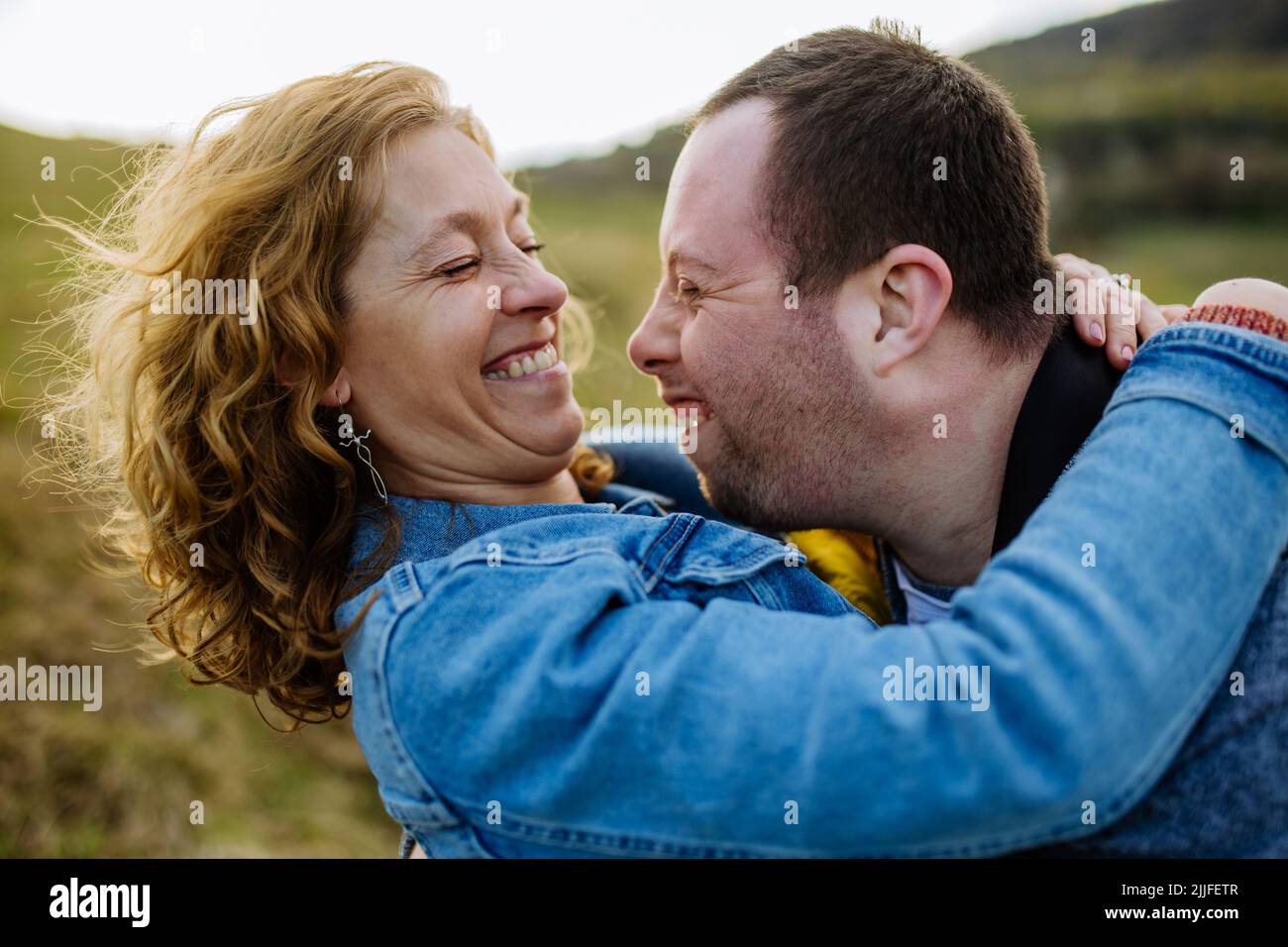 Outdoor portrait of mother hugging her grown up son with Down syndrome, motherhood concept Stock ...