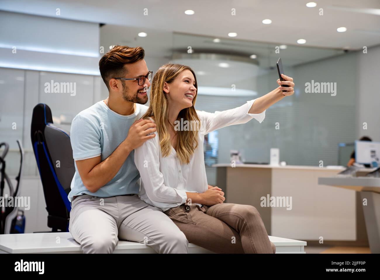 Portrait of a happy couple making a selfie in a tech store. Technology ...