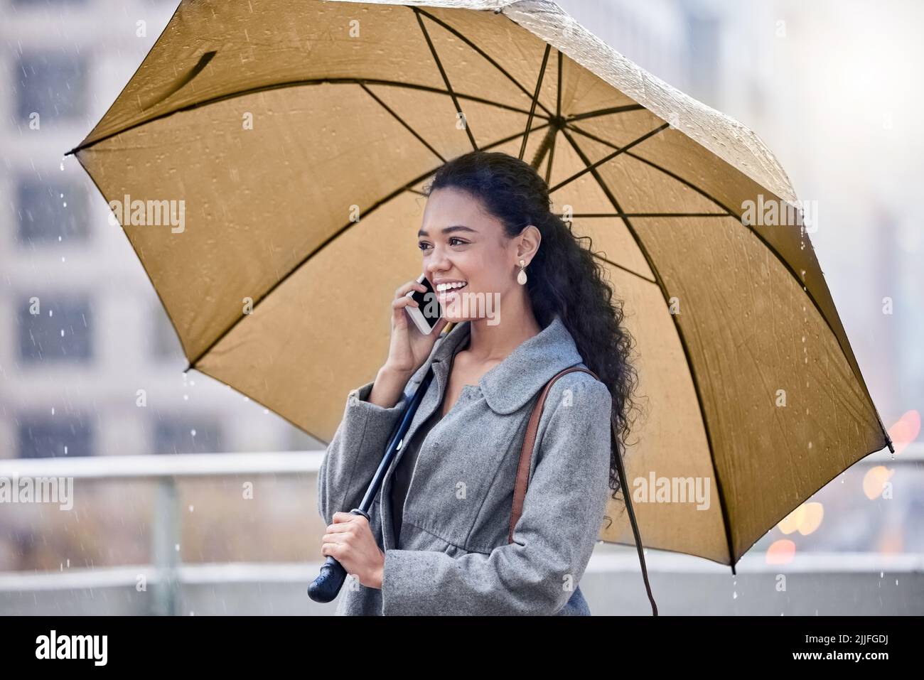 Im caught in the rain. a young woman holding an umbrella while on a ...