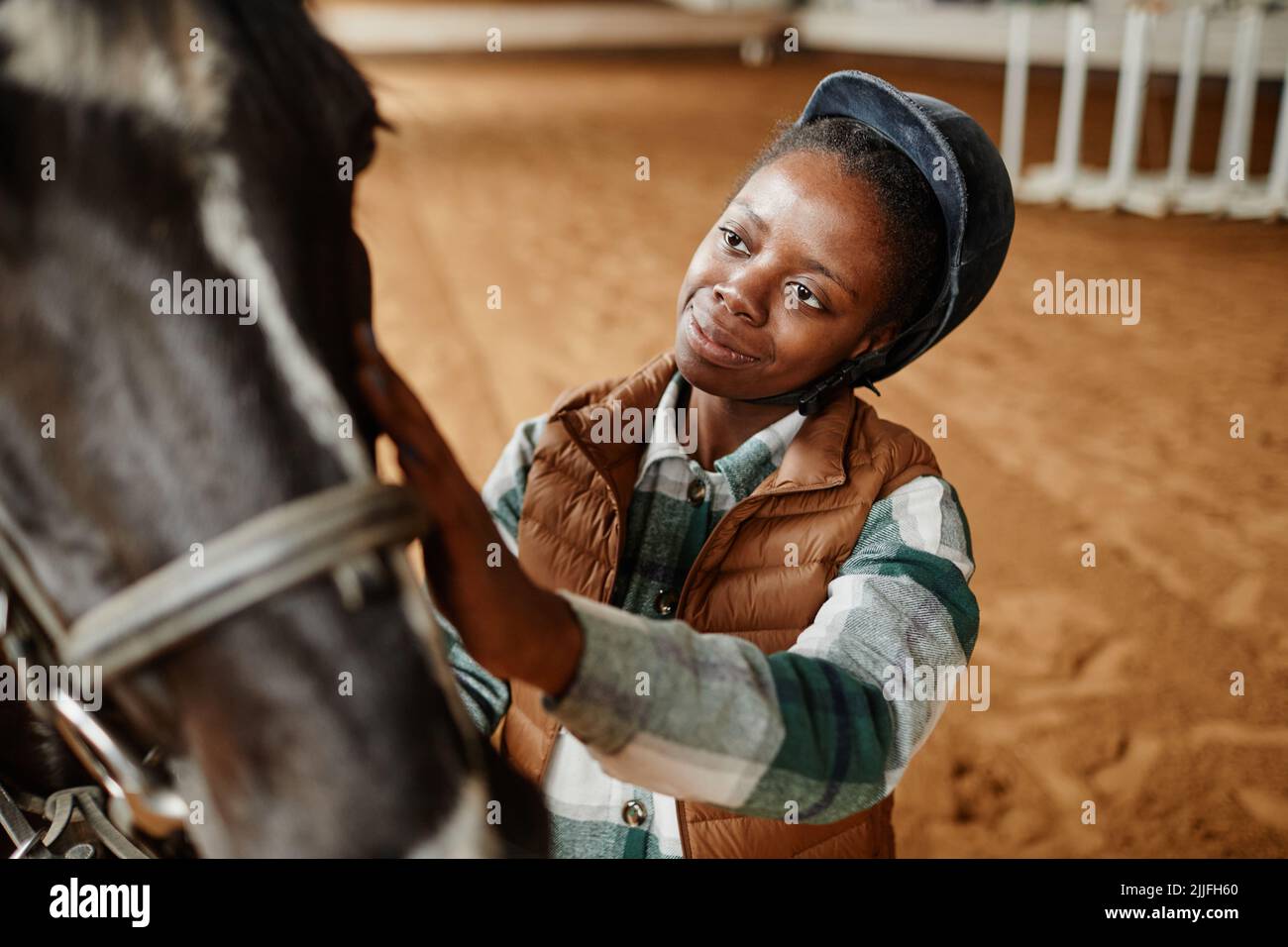 High angle portrait of young black woman caressing horse after sports ...
