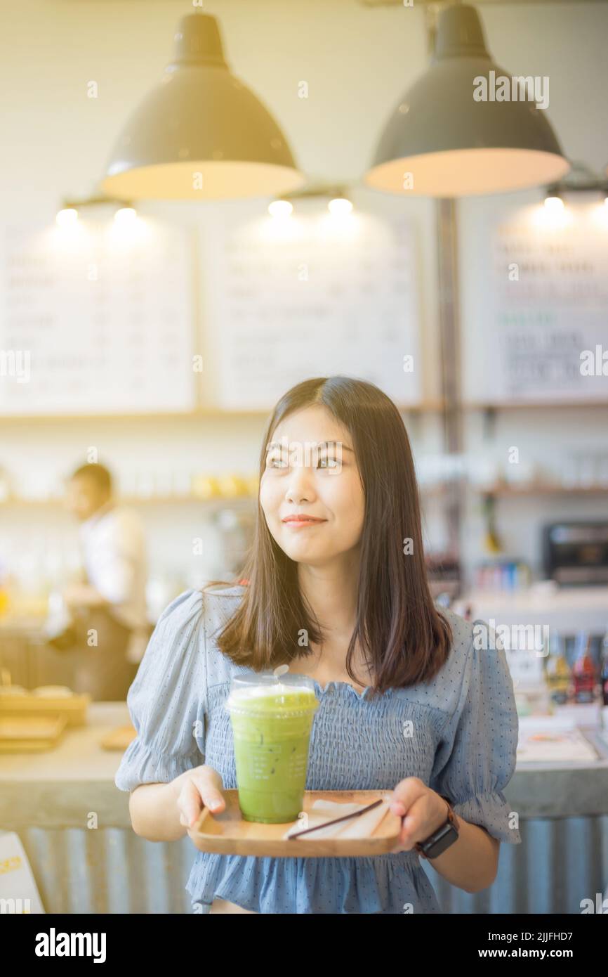 Happy smiling asian women drinking with ice matcha green tea indoor ...