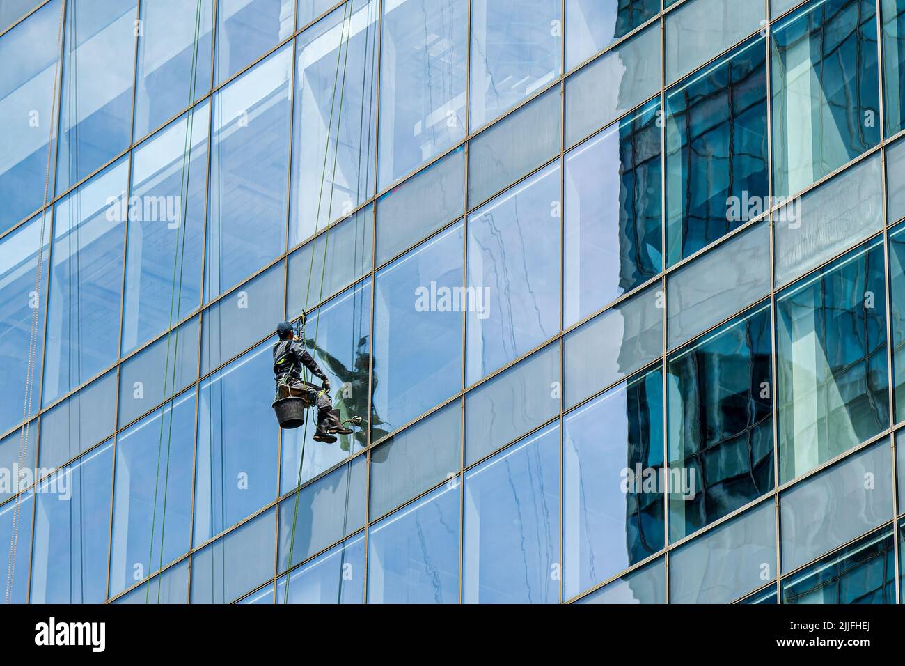 Industrial climber cleaning windows on the facade of an office building ...