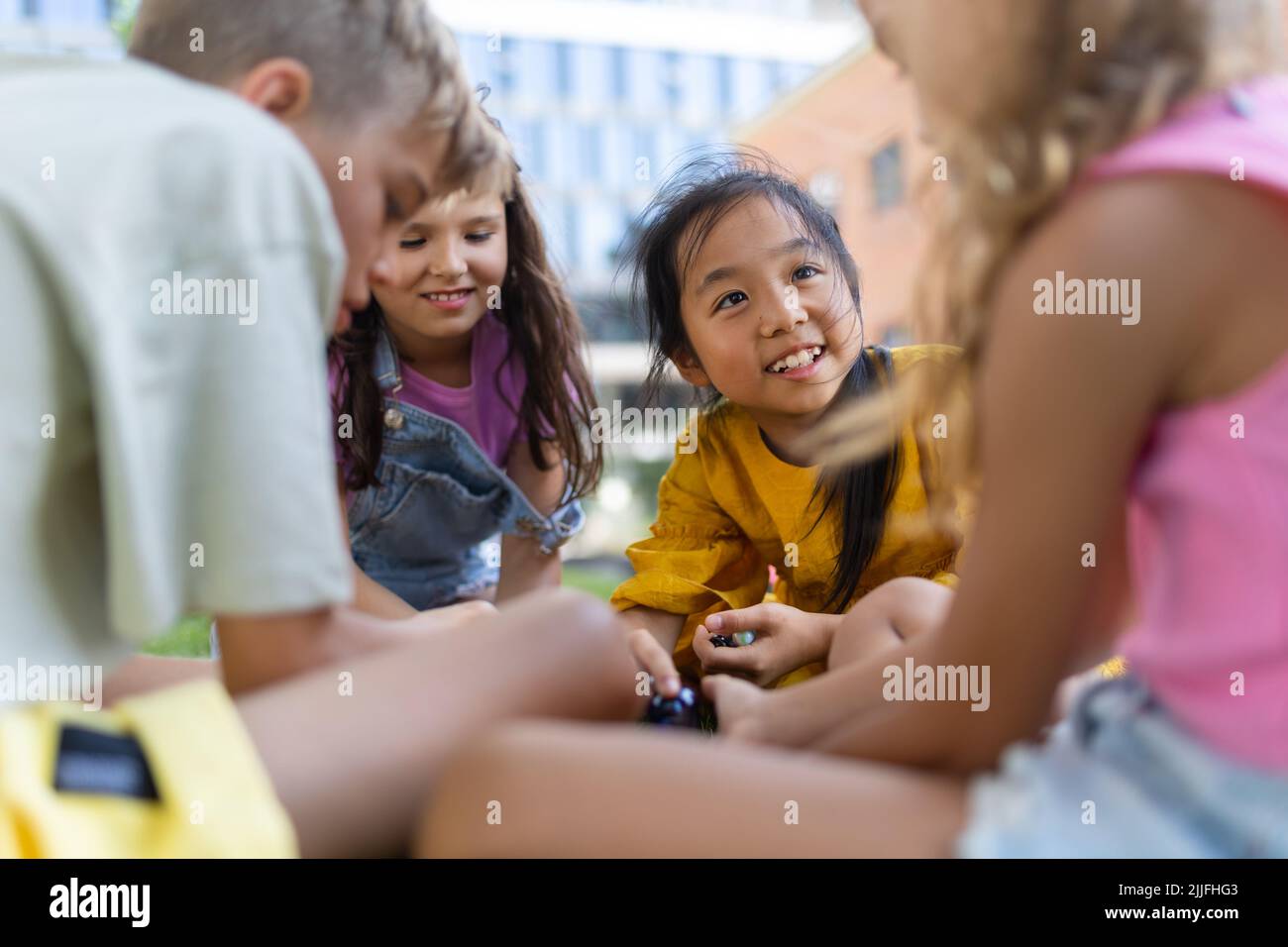 Happy kids playing and talking together in city park, during summer day ...