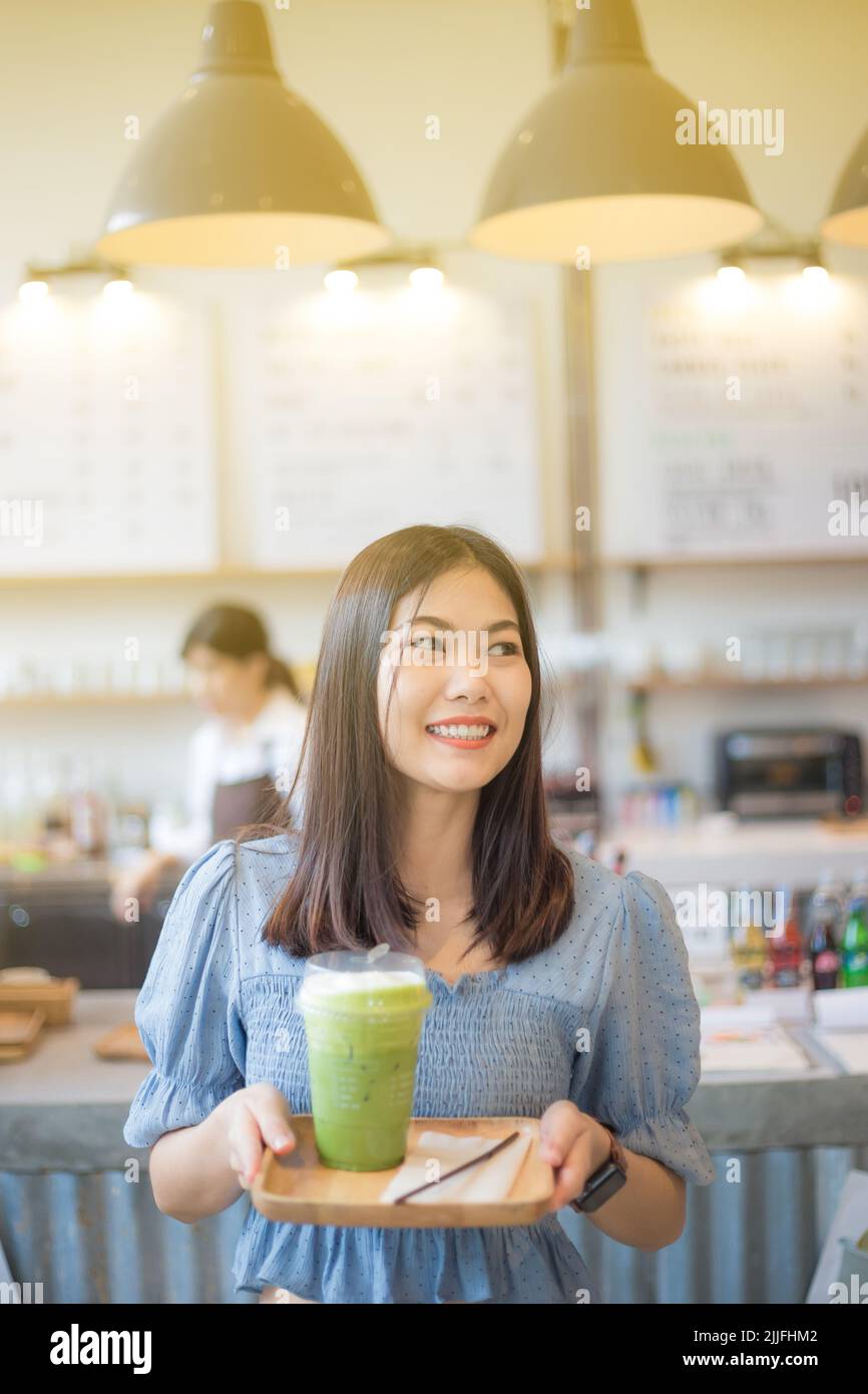 Happy smiling asian women drinking with ice matcha green tea indoor ...