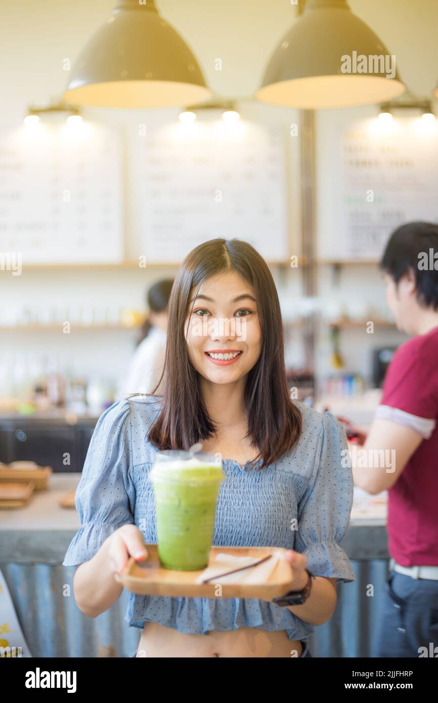Happy smiling asian women drinking with ice matcha green tea indoor ...