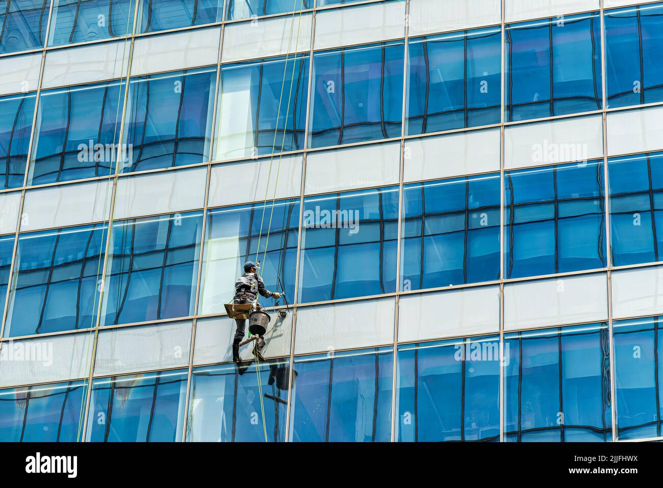 Industrial climber cleaning windows on the facade of an office building ...