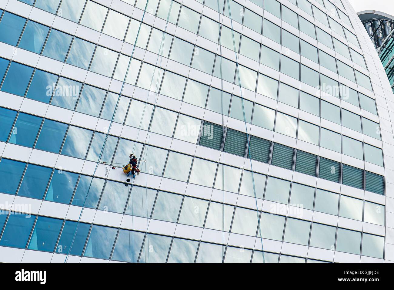 Industrial climber cleaning windows on the facade of an office building ...