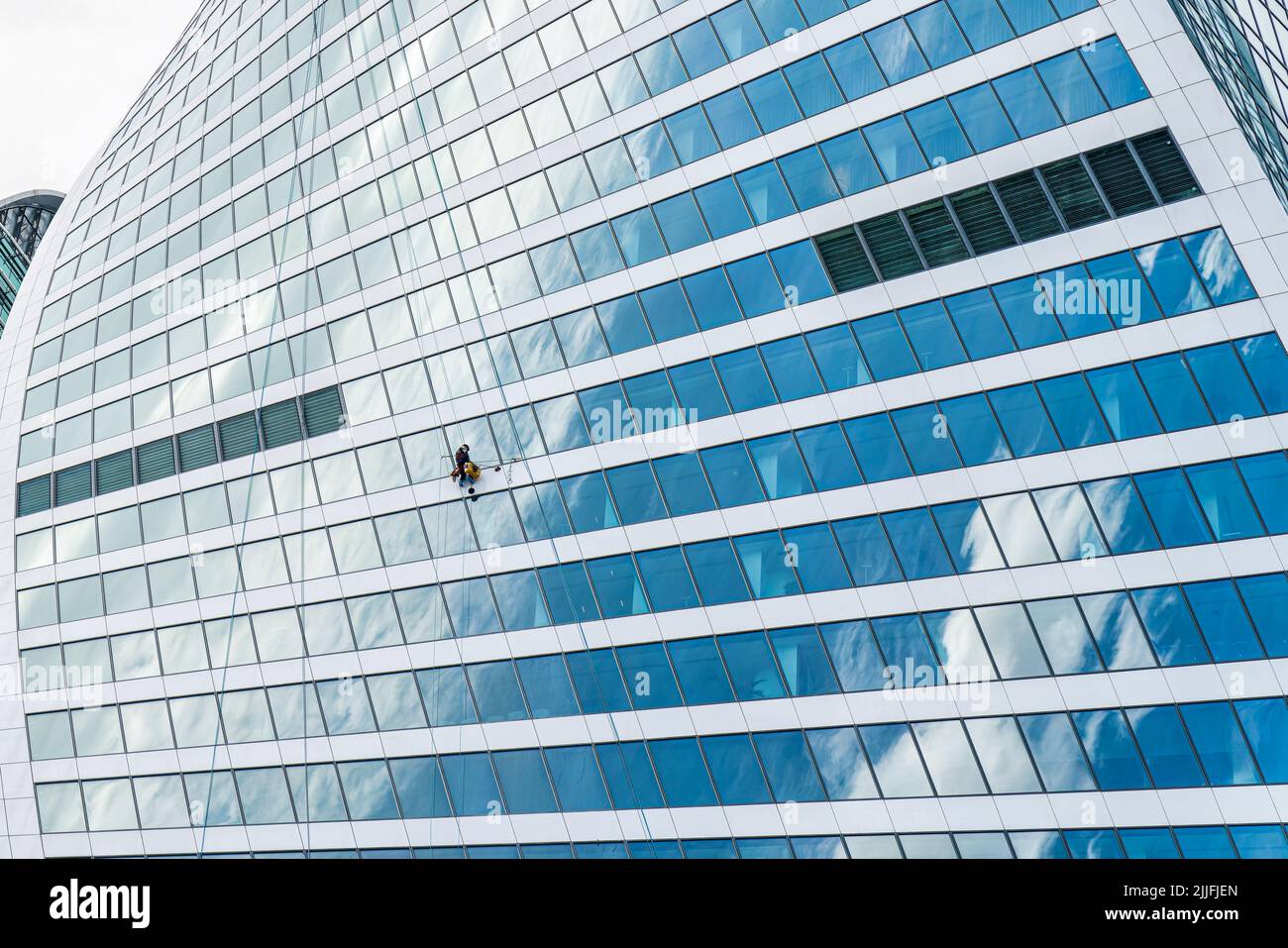 Industrial climber cleaning windows on the facade of an office building ...