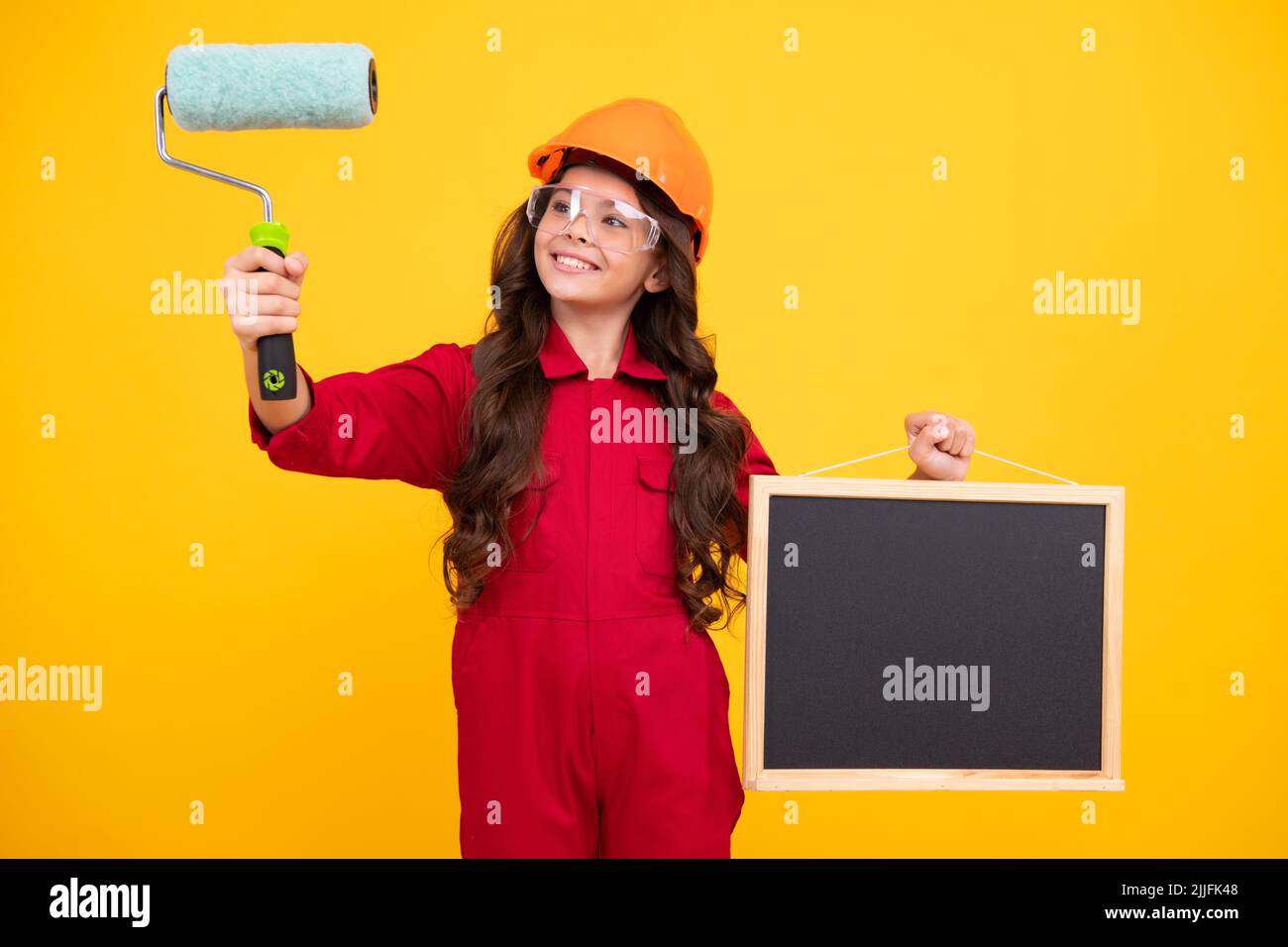 Little builder expert in helmet on construction site. Teen girl painter ...