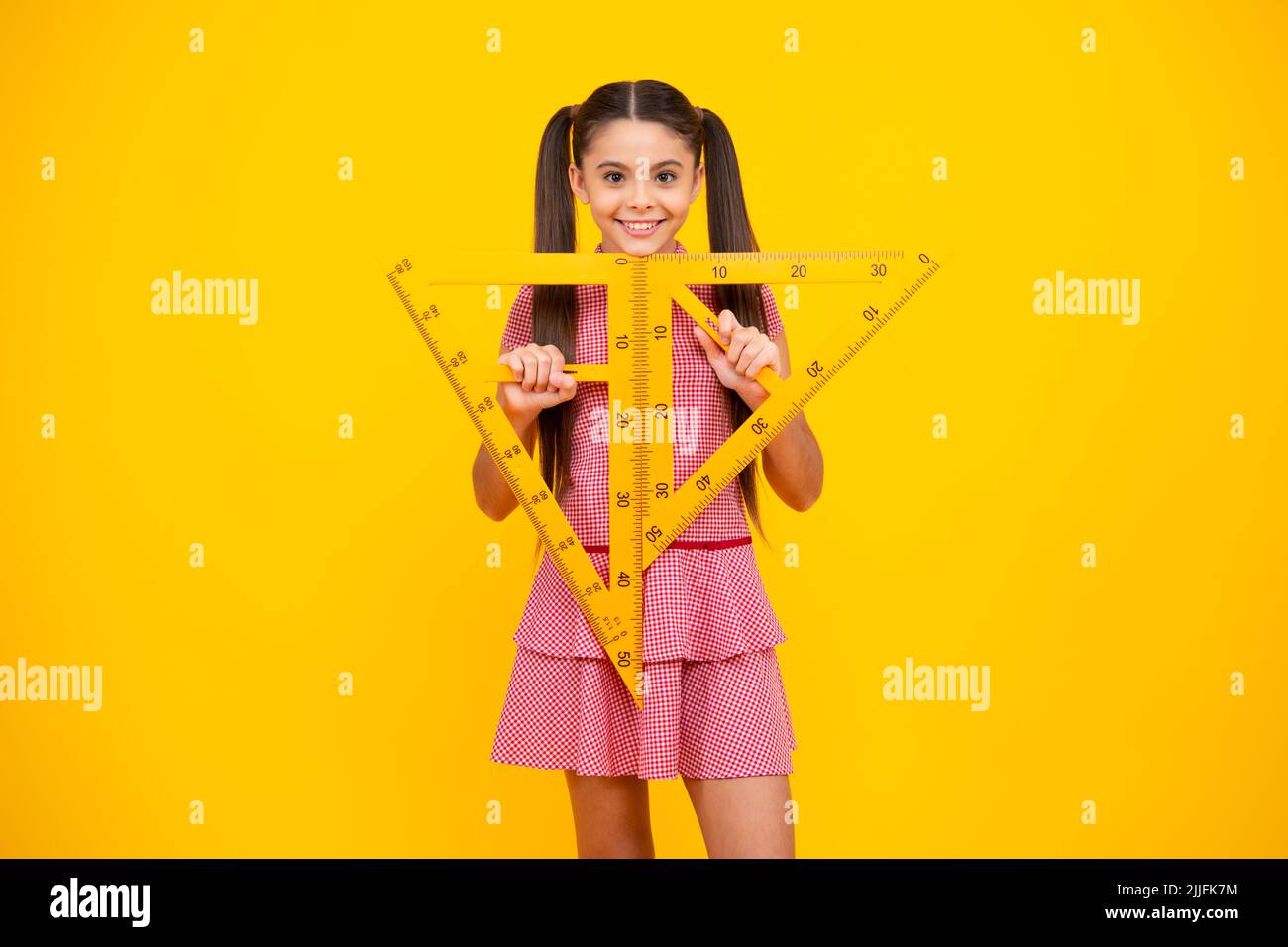 School girl holding measure for geometry lesson, isolated on yellow ...