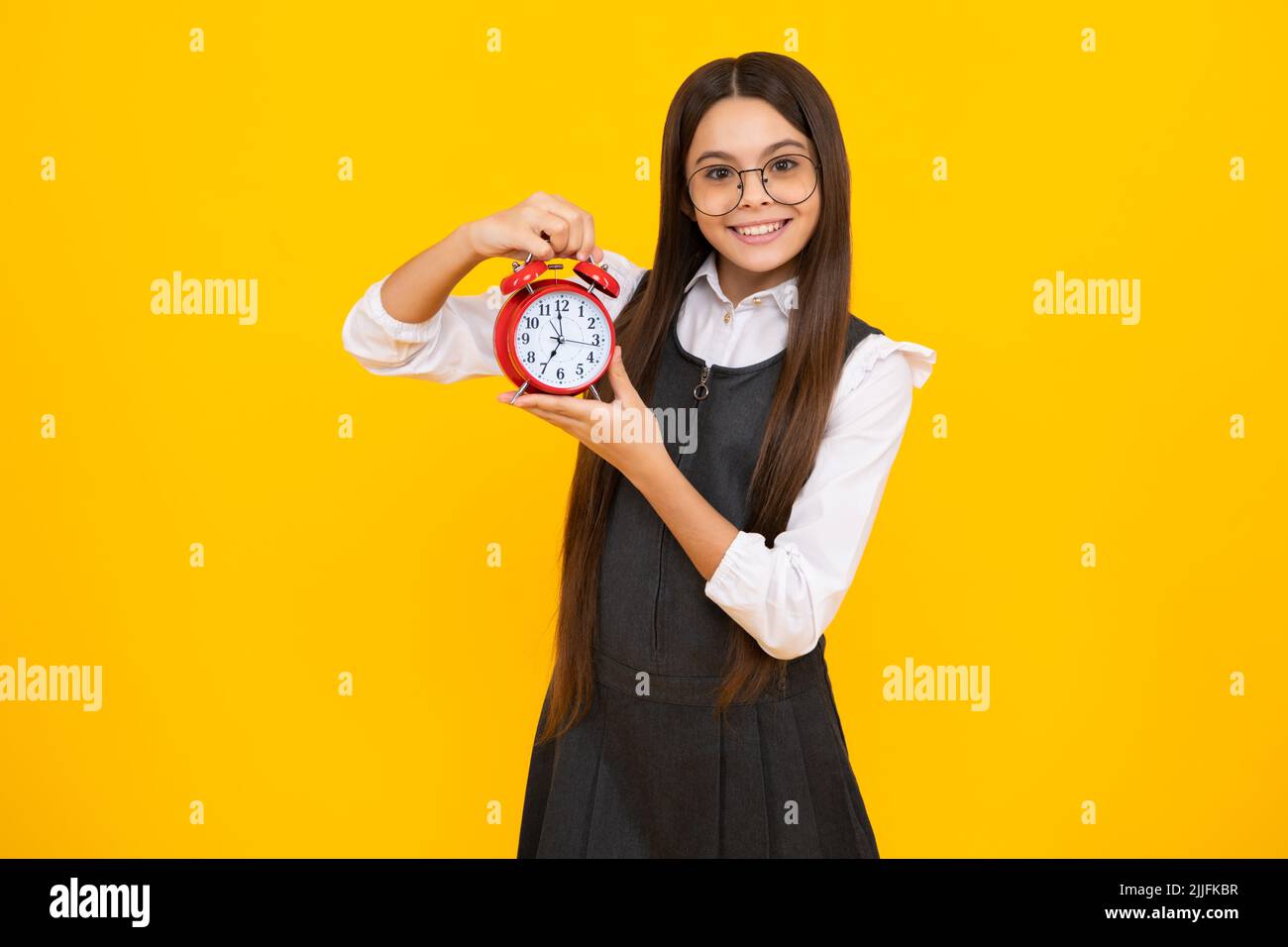 Child student girl with clock isolated on yellow background. Child back ...