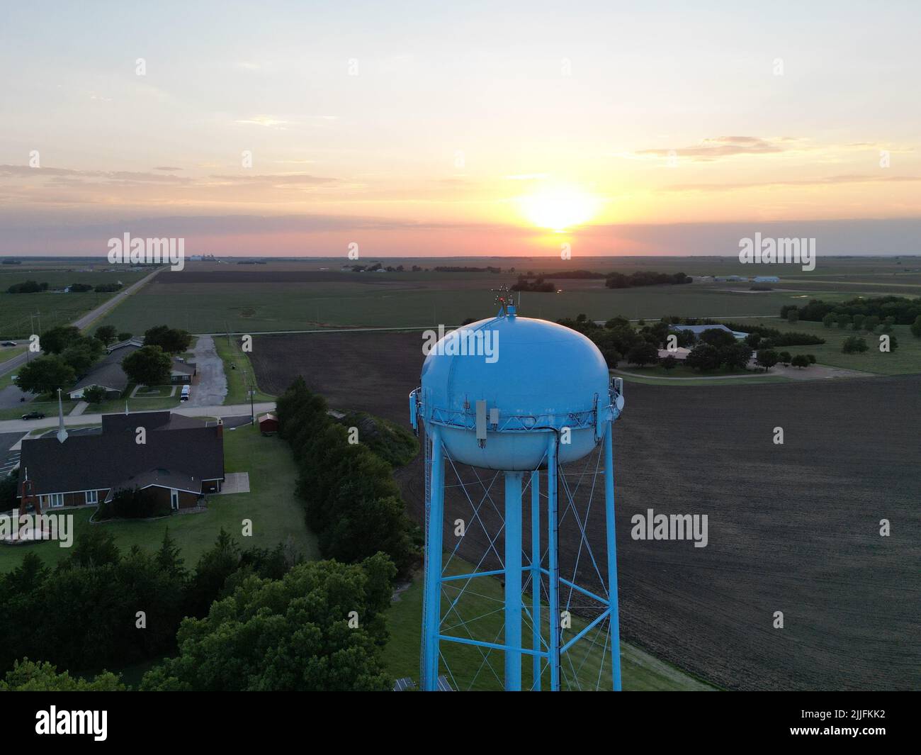 An aerial view of a Water Tower with fields in the background at sunset ...