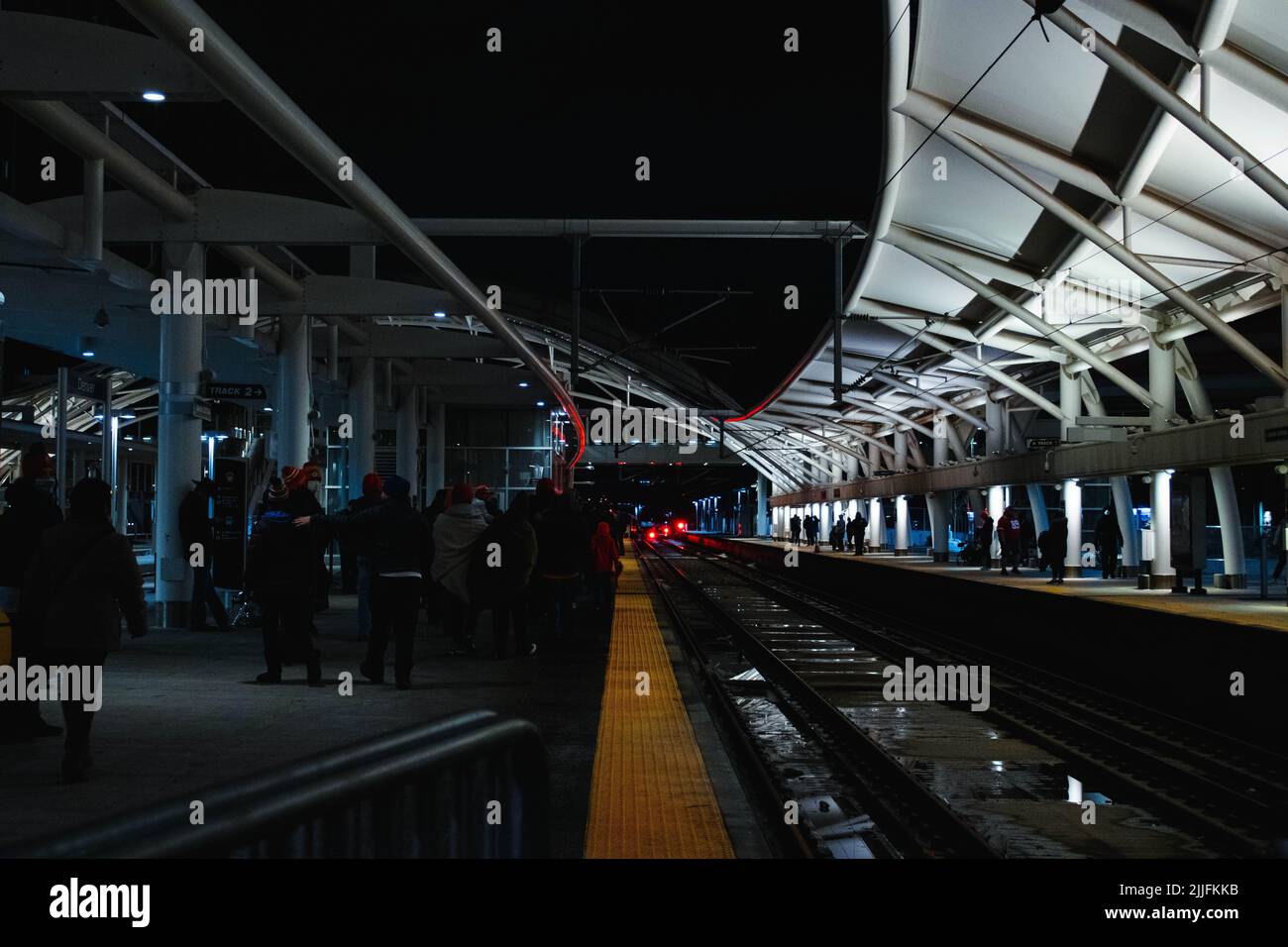 A wet train station at night with people Stock Photo - Alamy