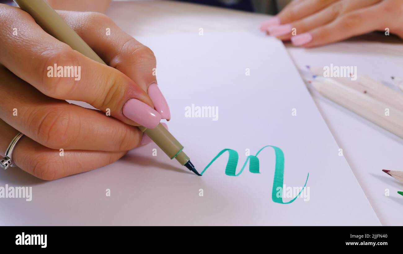 Calligrapher hands writes word on white paper. Inscribing ornamental ...