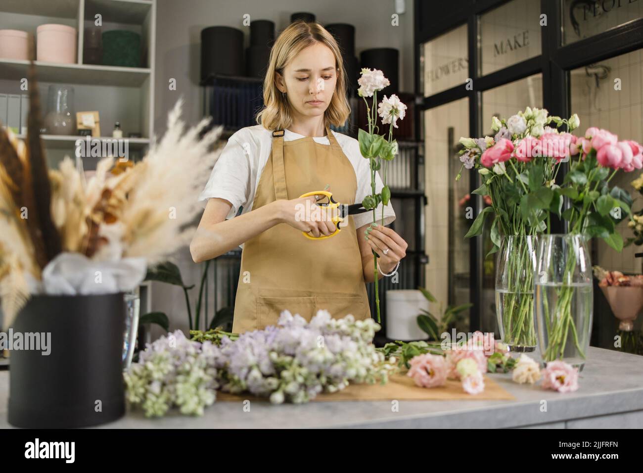 Cute girl florist collects a bouquet of roses in a flower shop. A ...