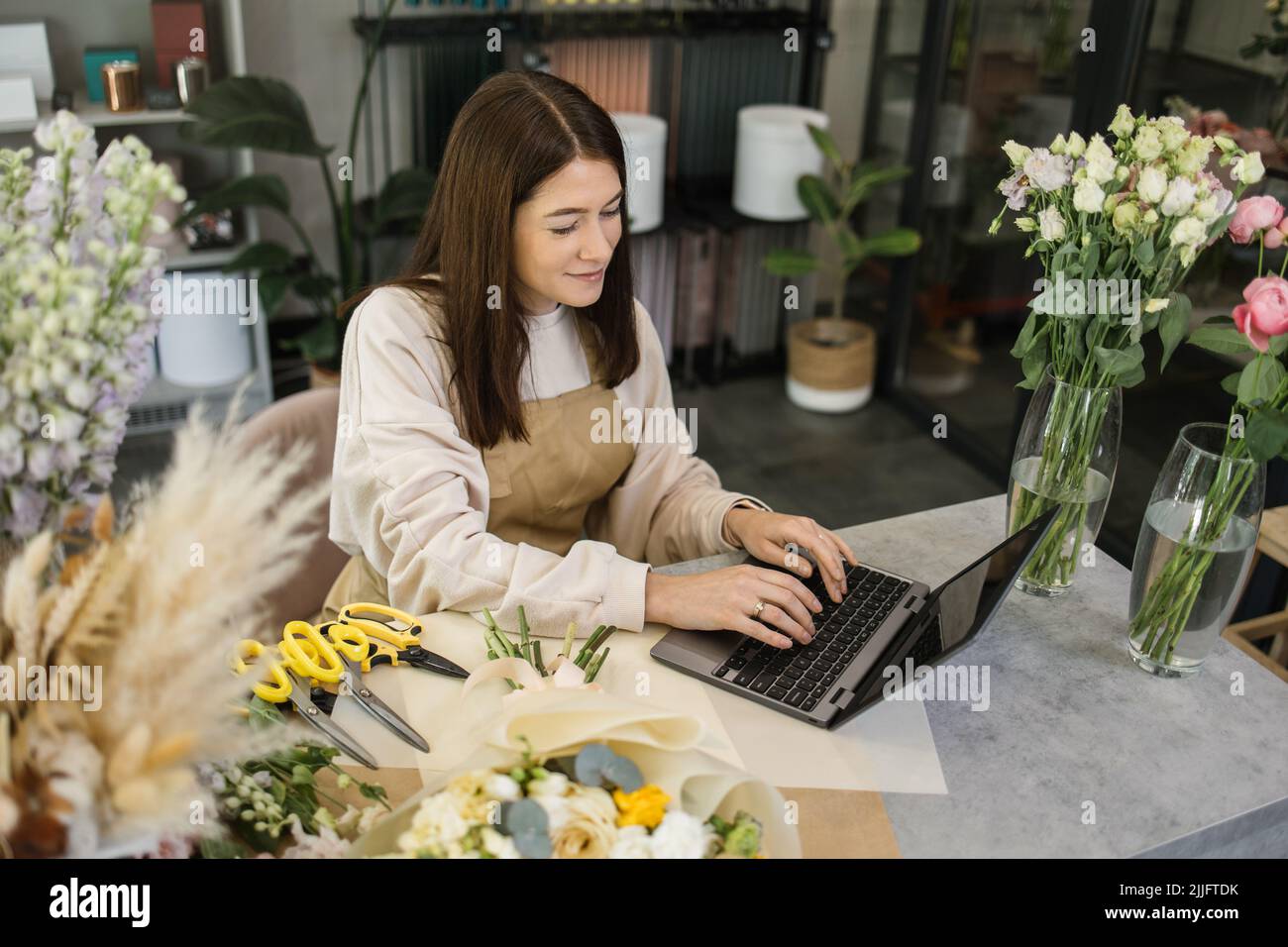 Portrait of attractive woman florist working on computer at workplace ...