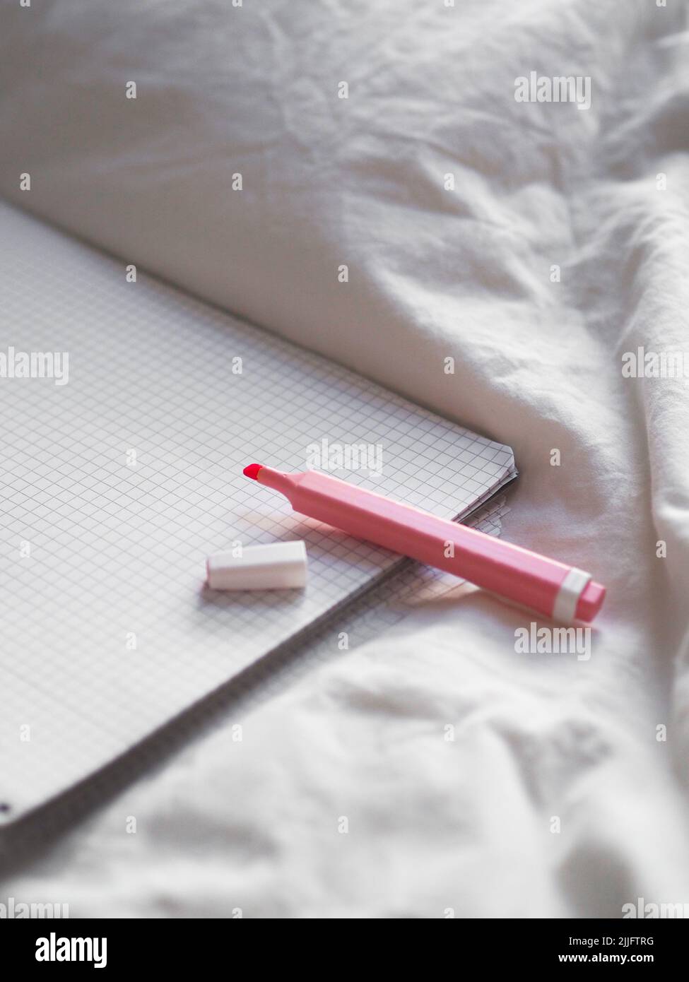 A vertical of a squared notebook page with an open pink highlighter on ...
