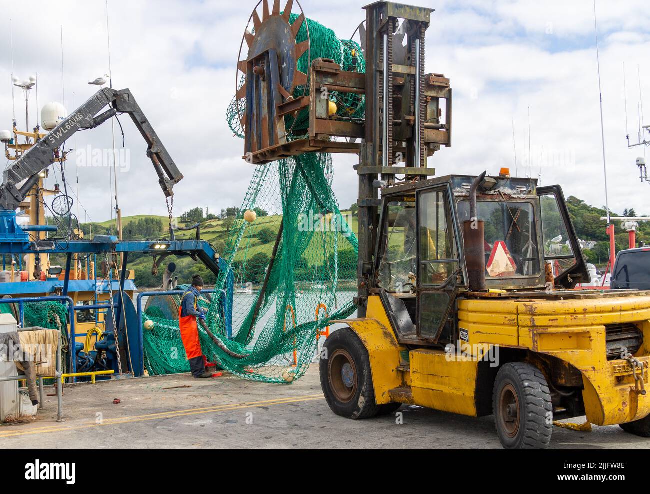 Fishing Trawler loading nets onboard from a reel on forklift truck ...