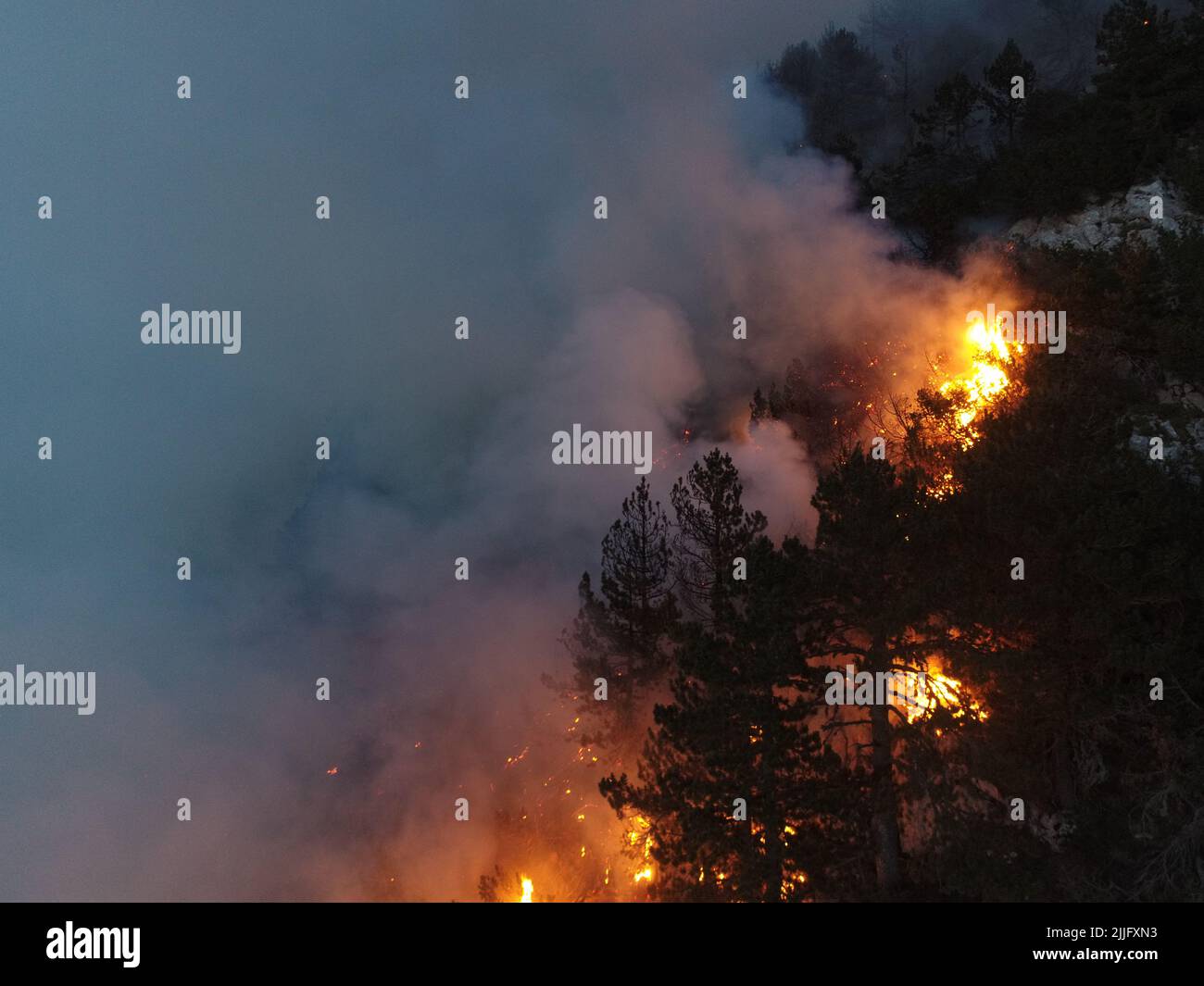 Aerial panoramic view of a forest fire at night, heavy smoke causes air ...