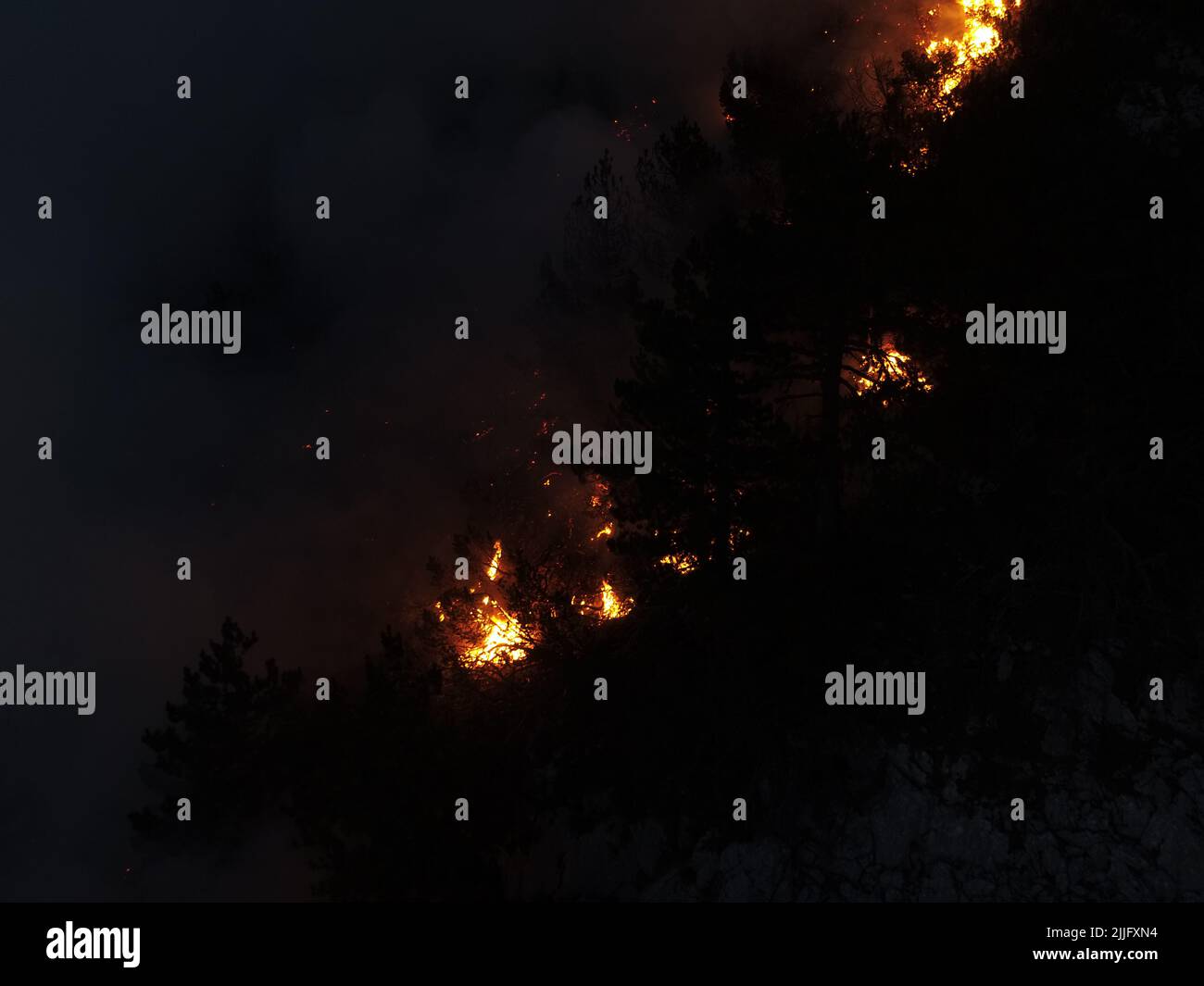 Aerial panoramic view of a forest fire at night, heavy smoke causes air ...
