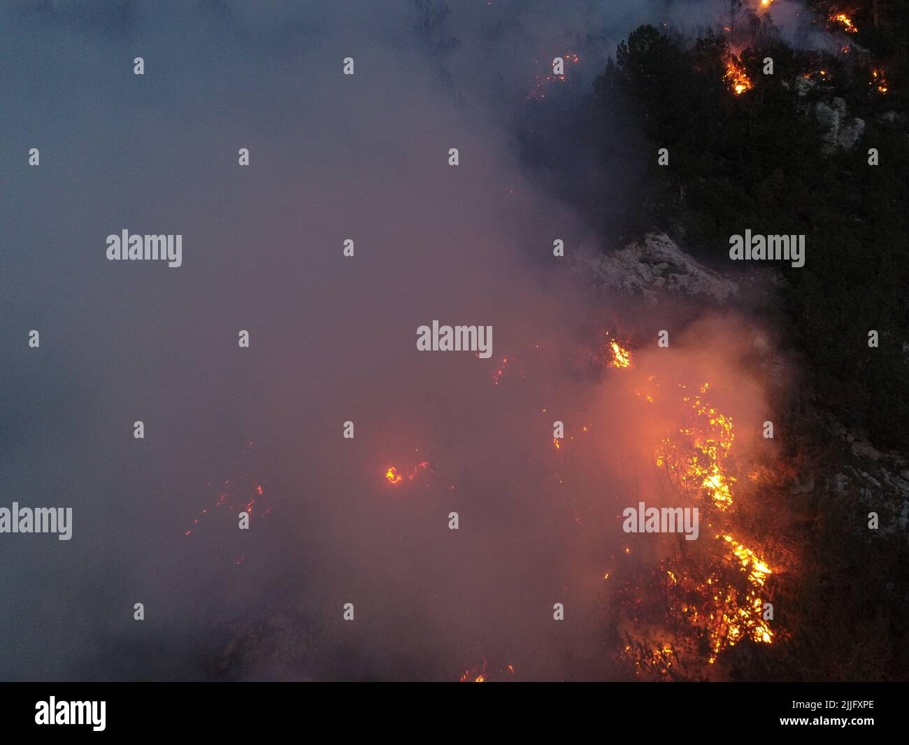 Aerial panoramic view of a forest fire at night, heavy smoke causes air ...