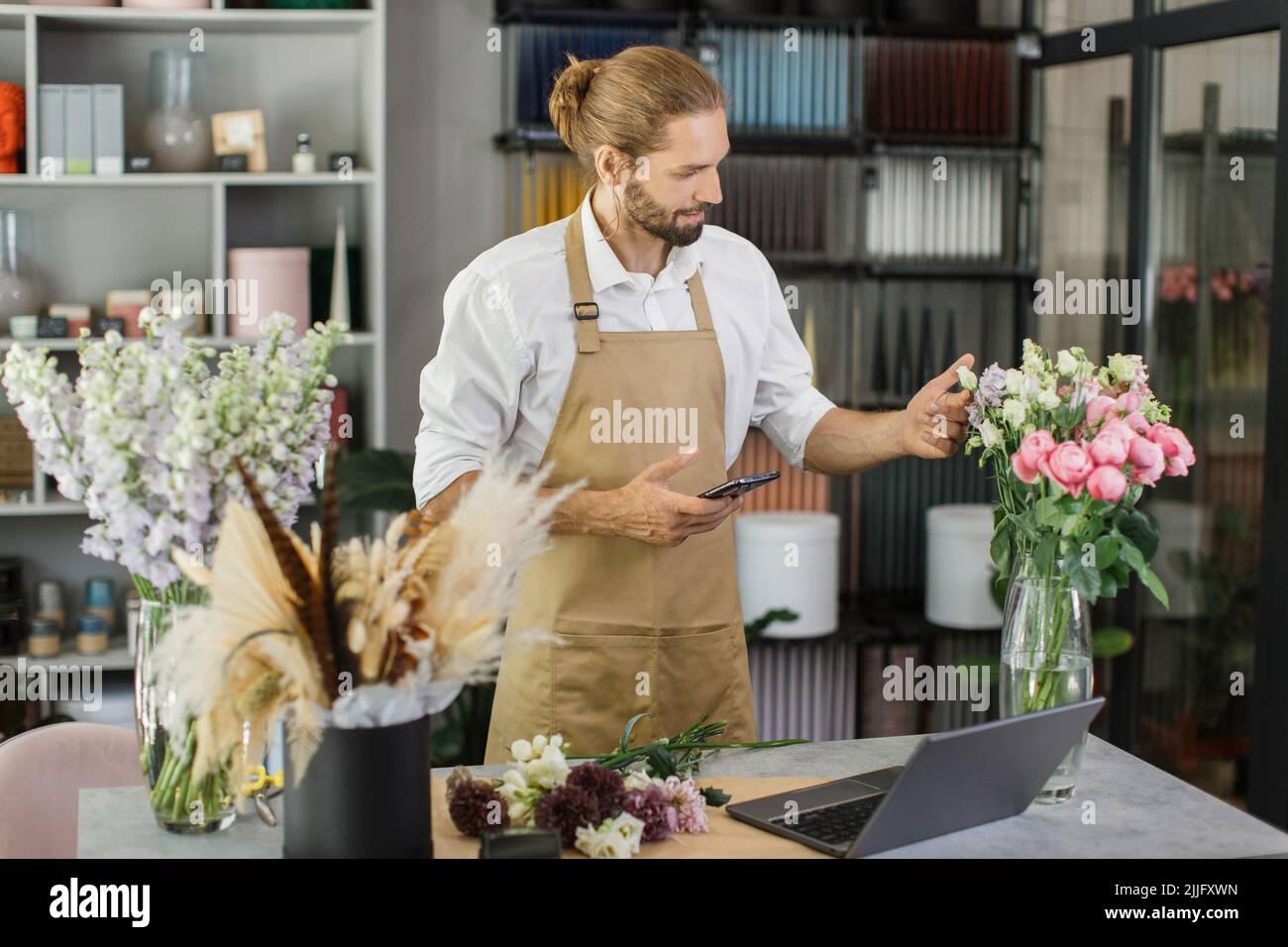 Caucasian male florist making bouquet at work in floral shop and taking ...