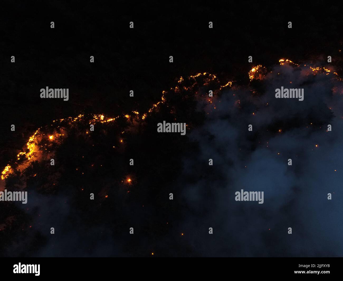 Aerial panoramic view of a forest fire at night, heavy smoke causes air ...