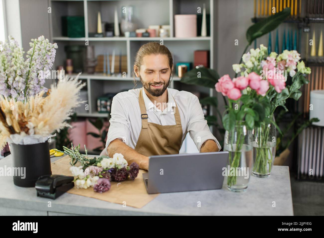 Portrait of attractive man florist working on computer at workplace ...