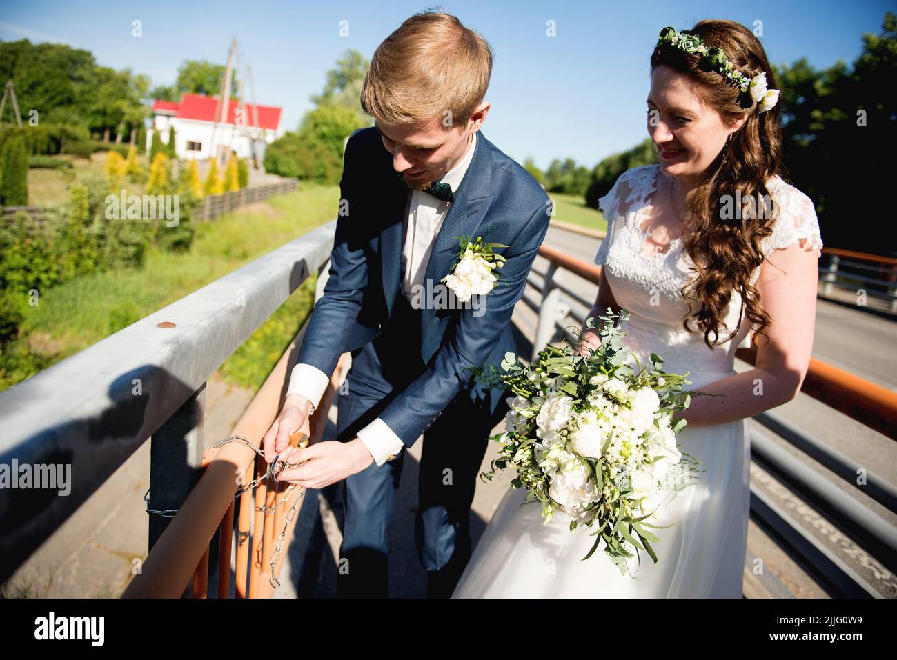 A closeup shot of a young bride and groom unlocking a traditional gate ...
