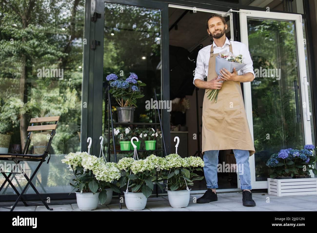Business man near flower shop door. Photo of handsome man standing in ...