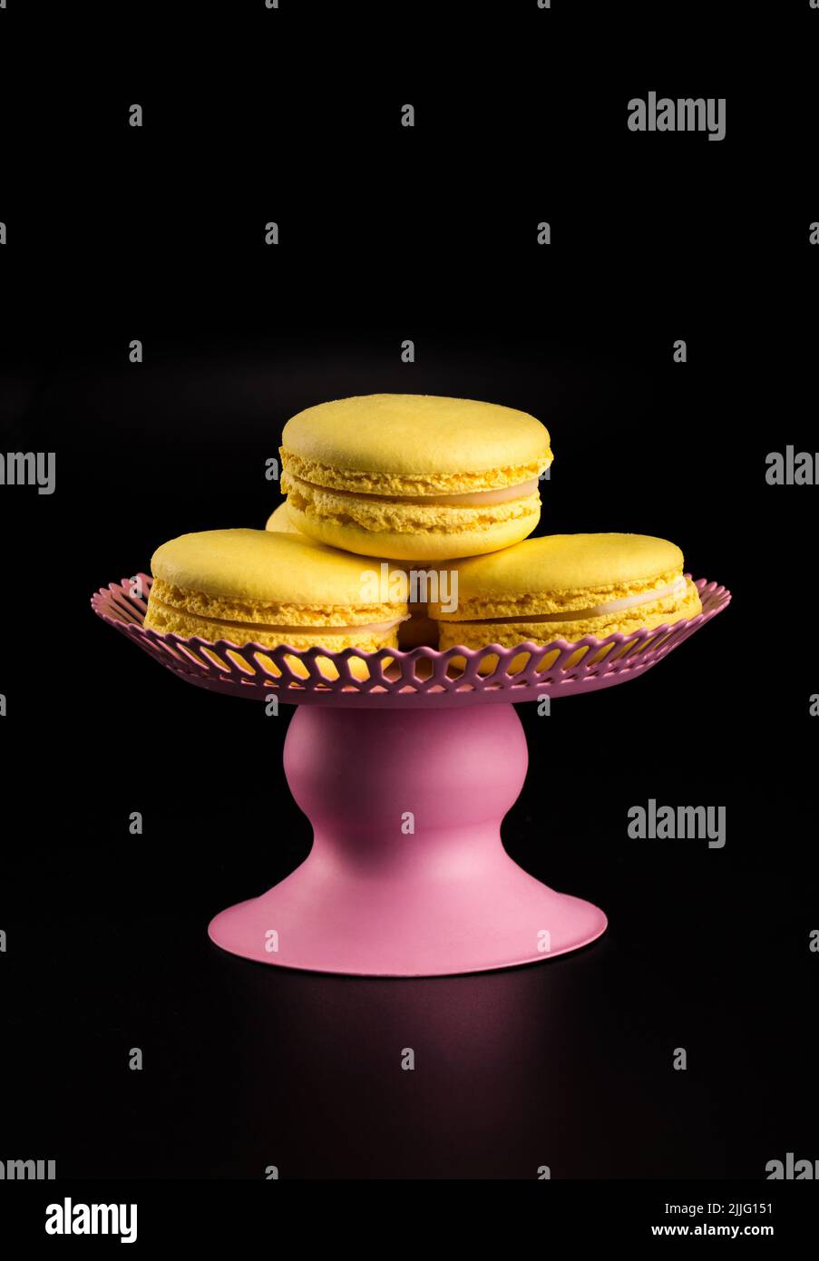 Yellow Macarons on a black background French pasta. Stack of yellow ...